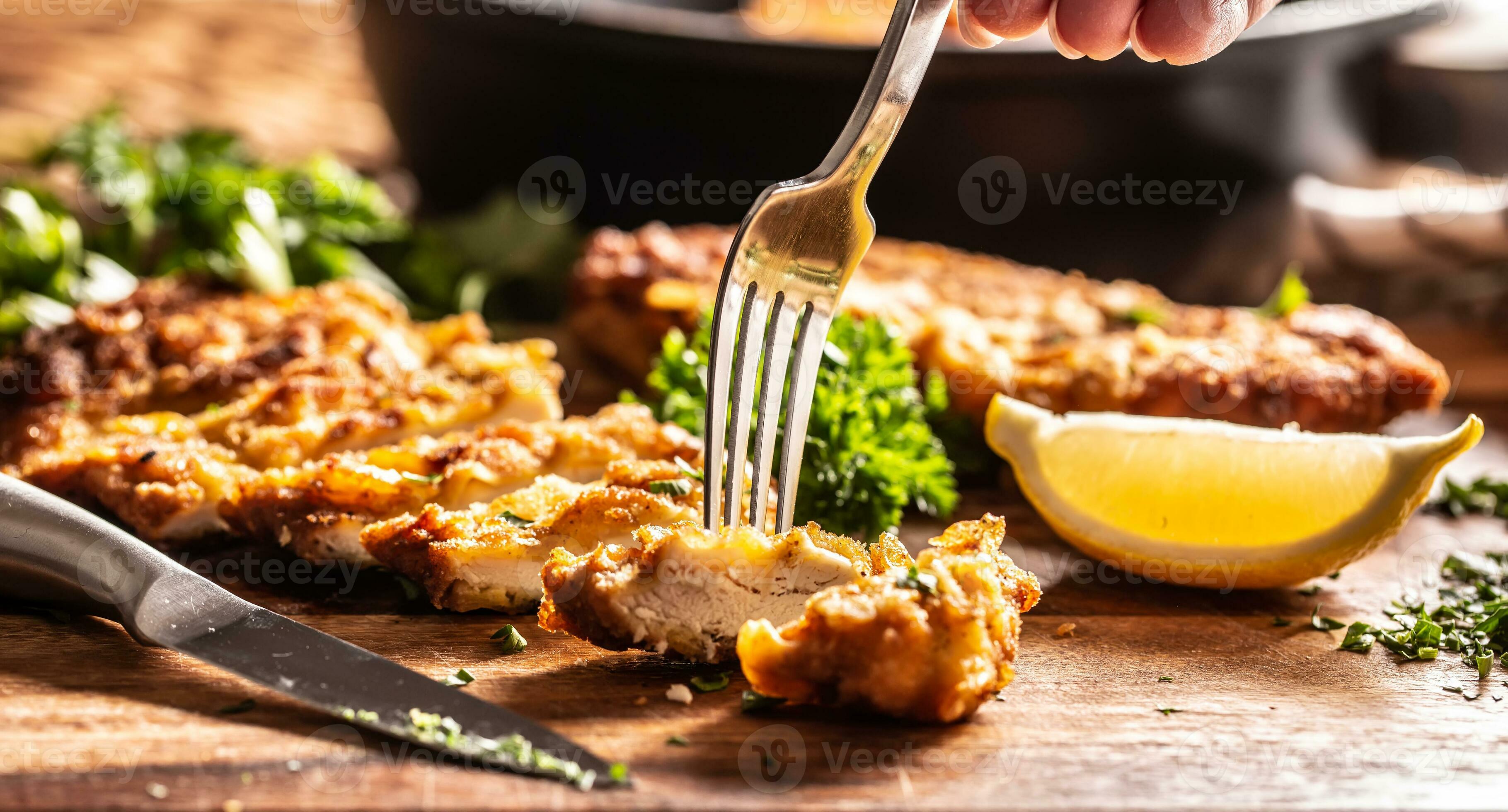 Viennese chicken steak on a fork. Traditional Austrian and German dish of chicken meat and ...