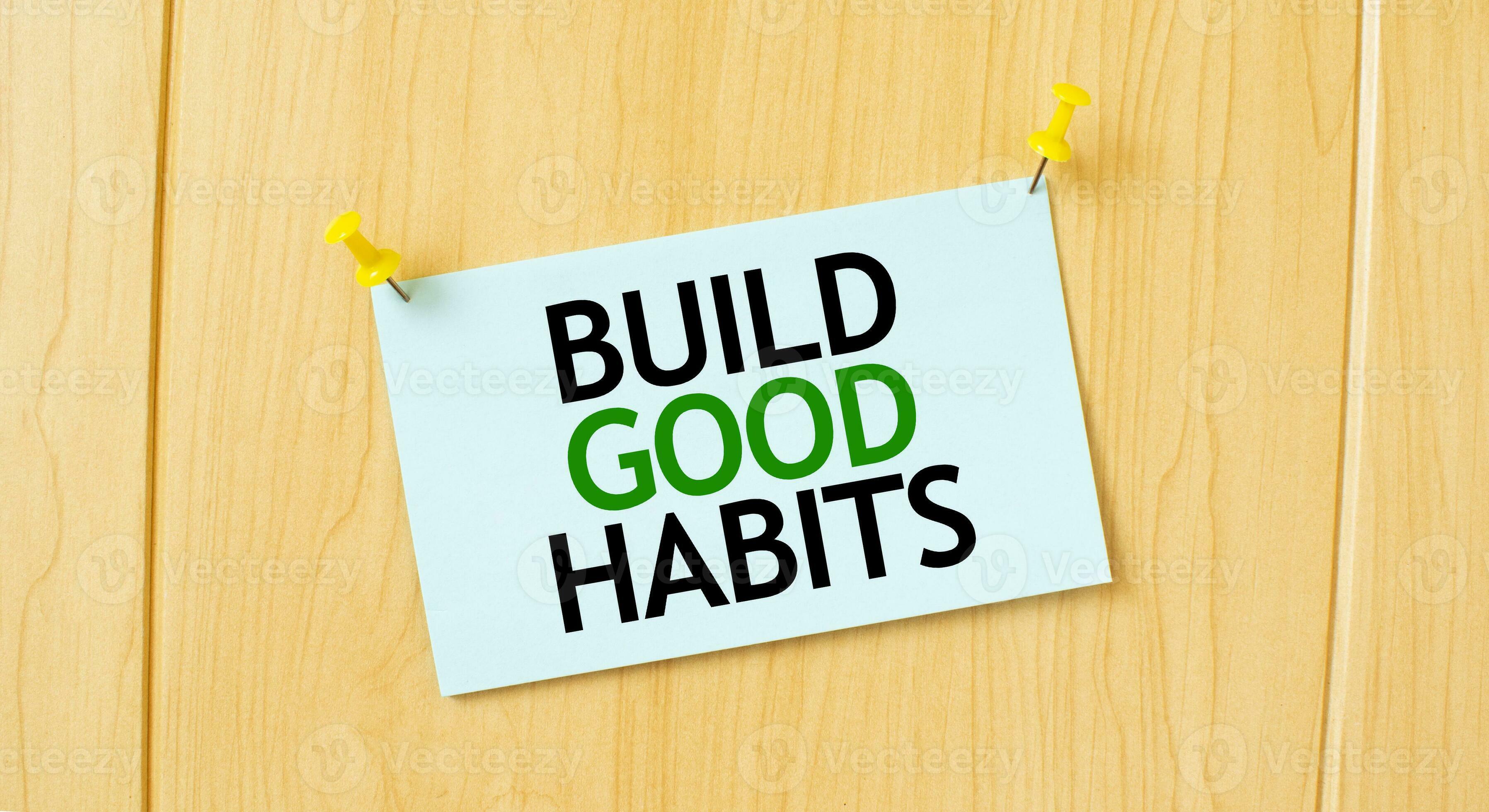 BUILD GOOD HABITS sign written on sticky note pinned on wooden wall ...