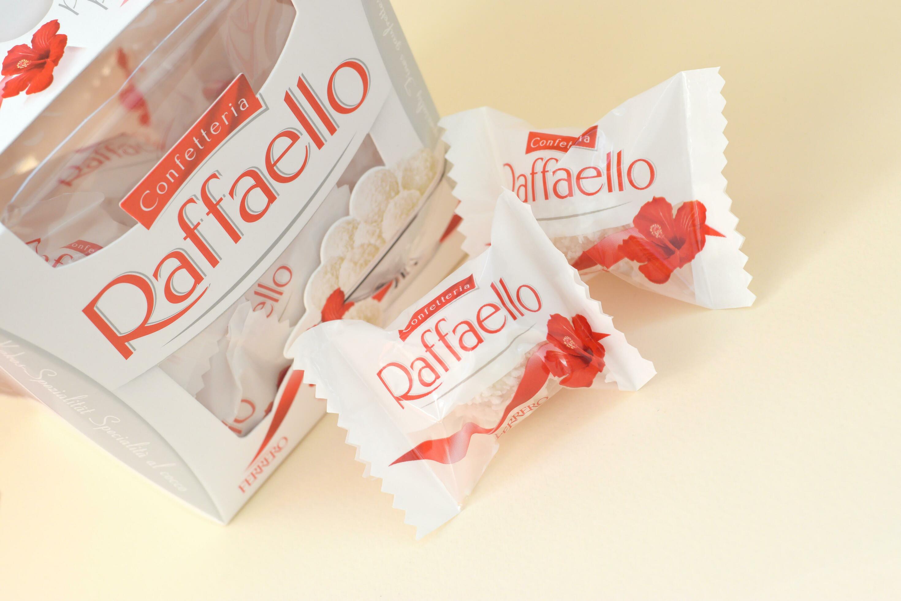 Raffaello candies on beige background. Raffaello is a spherical coconut almond confection that ...