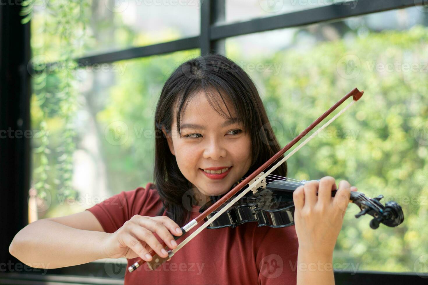 An attractive woman learning musician plays the violin at home ...