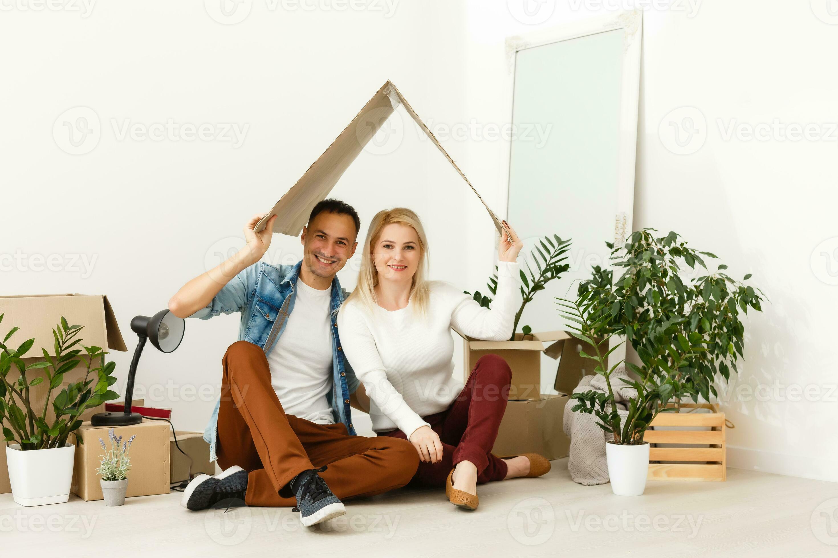Young Couple Carrying Big Cardboard Box At New Home Moving House