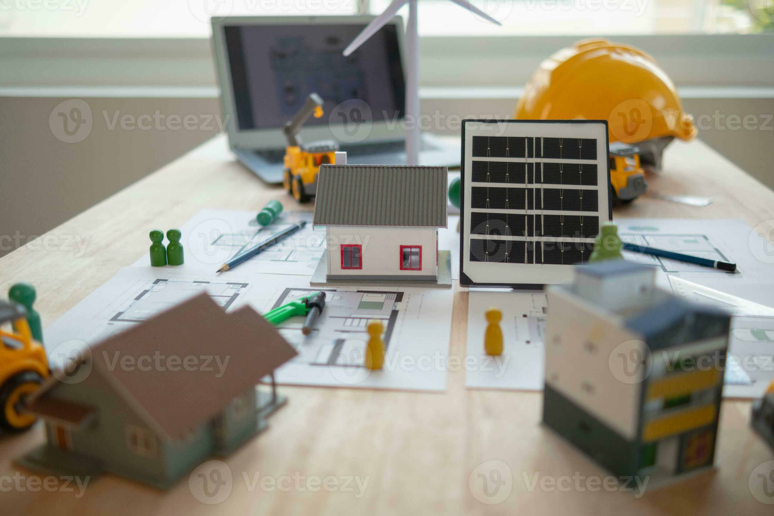On desk of engineers lay model of house And solar panels to use in ...