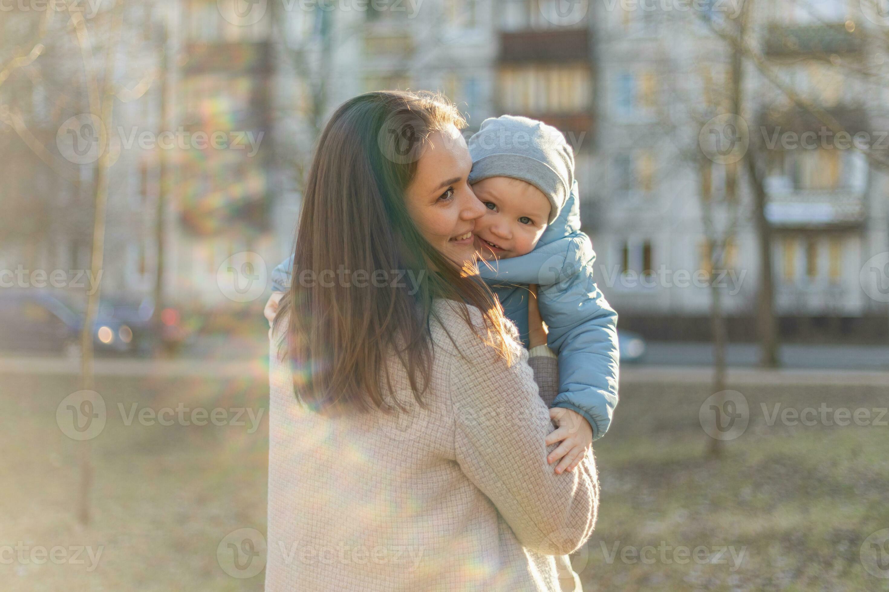 Happy family outdoor. Mother embracing her child outdoor. Mom lifting in air little toddler ...