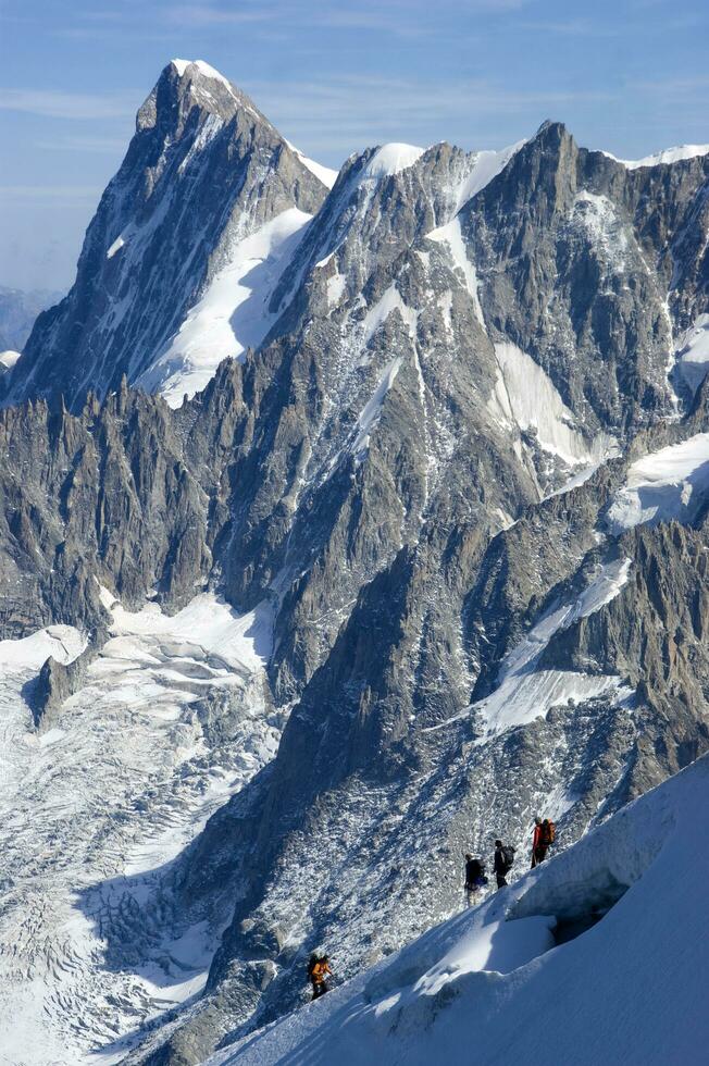 two people are hiking up a mountain with snow covered mountains ...