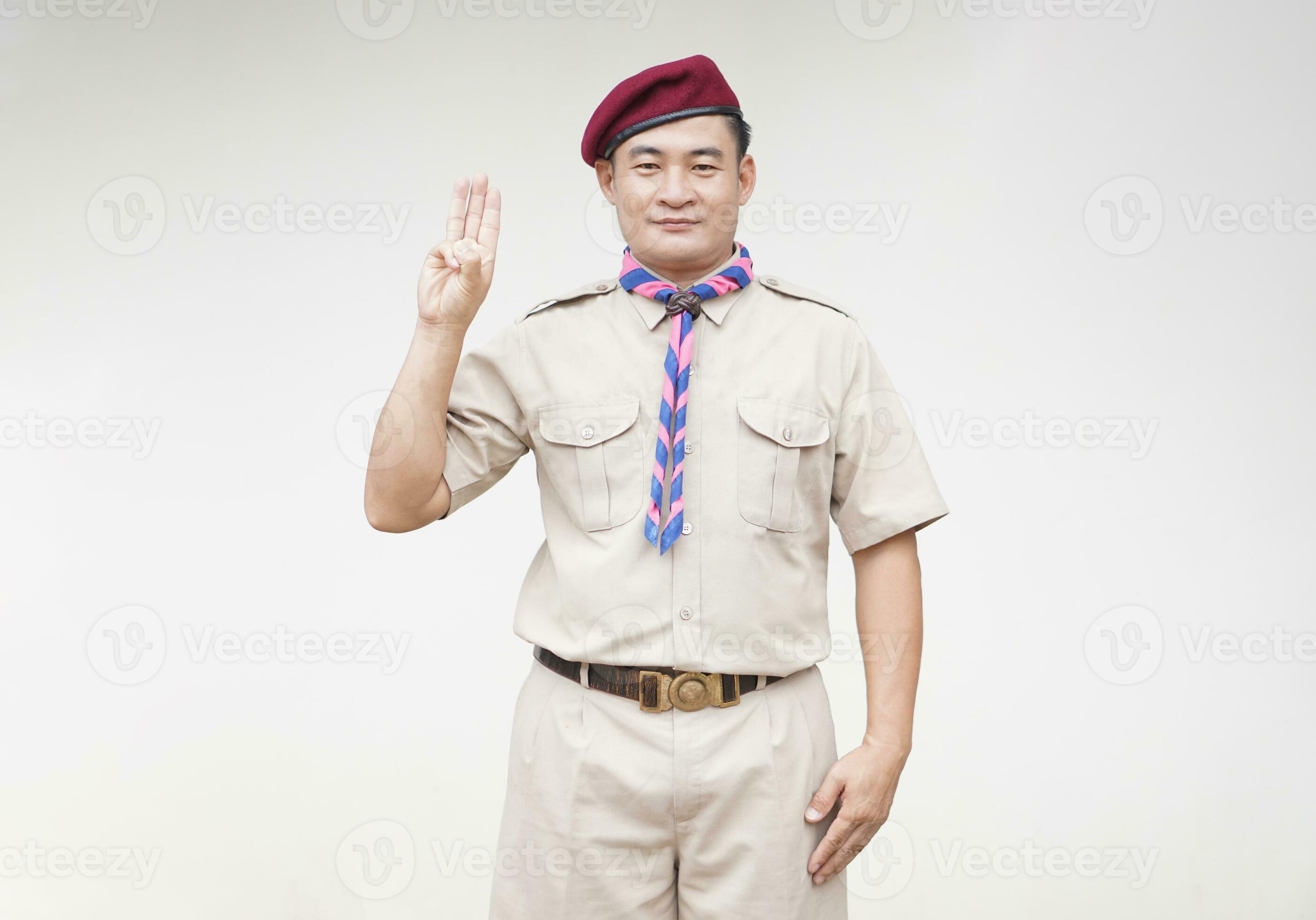 Handsome Asian man wear boy scout uniform, red cap, blue and pink striped scarf, make hand sign ...