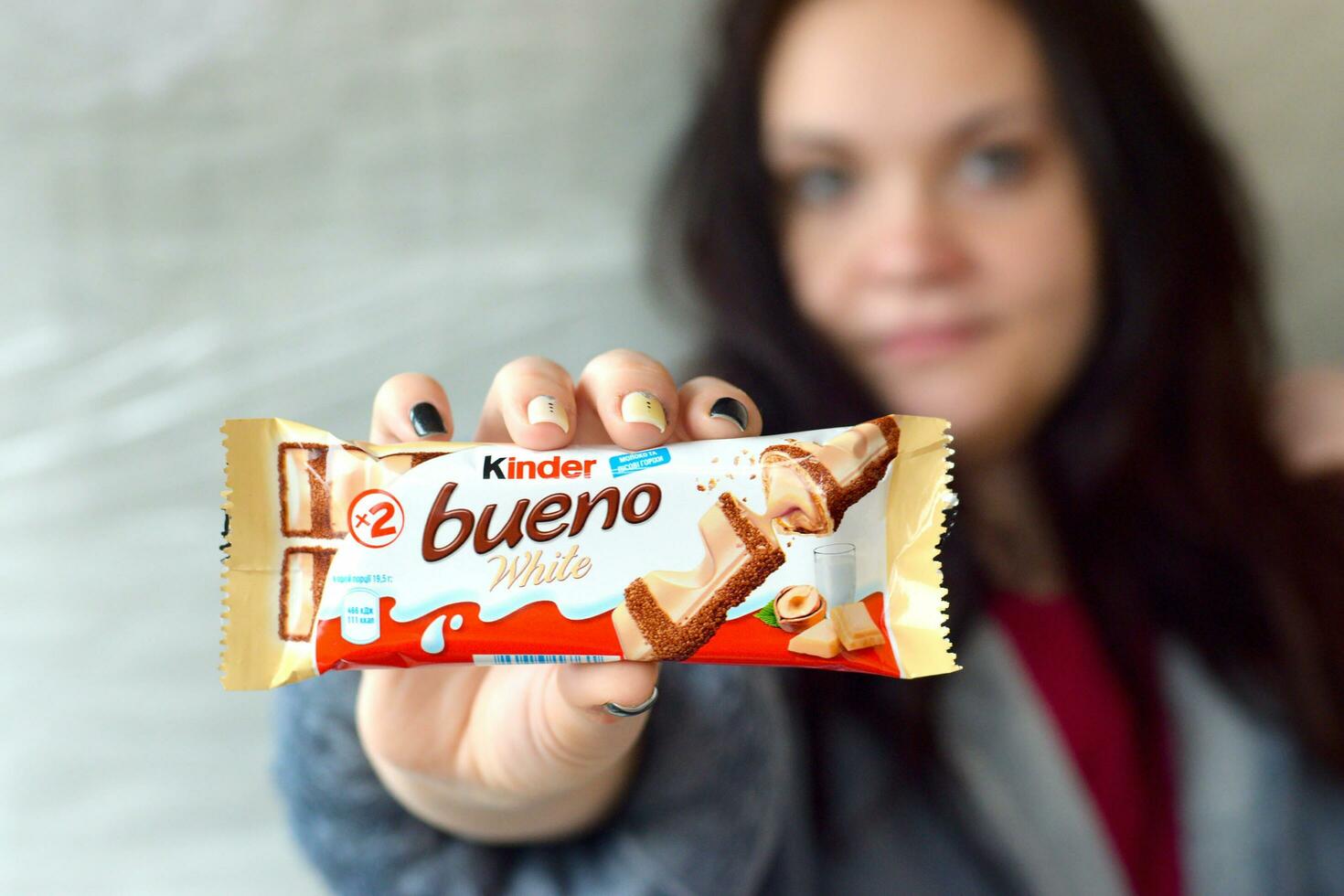 Young Woman Shows Kinder Bueno White Chocolate Candy Bar In Colored Wrapping Kinder Bueno By
