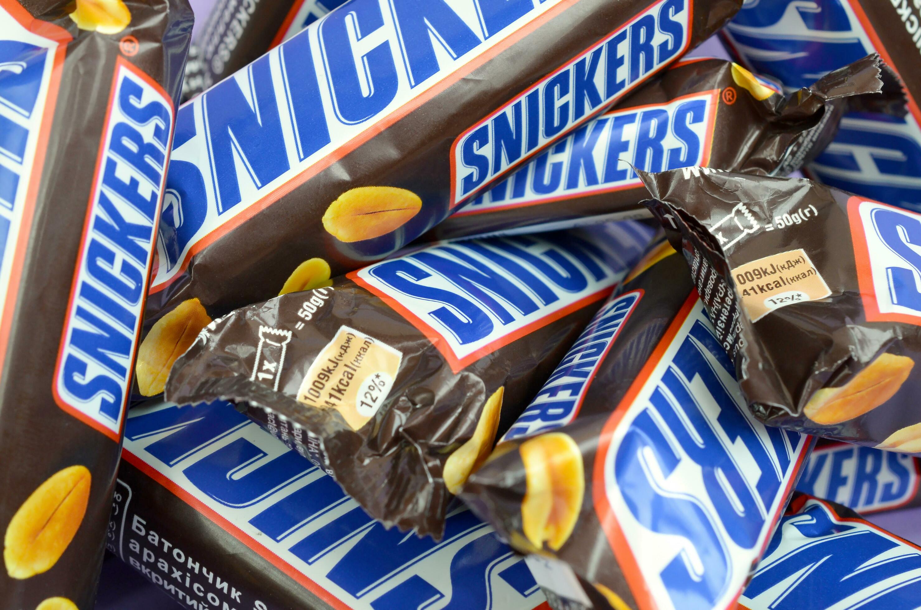Many Snickers chocolate bars stacked close up. Snickers bars are ...