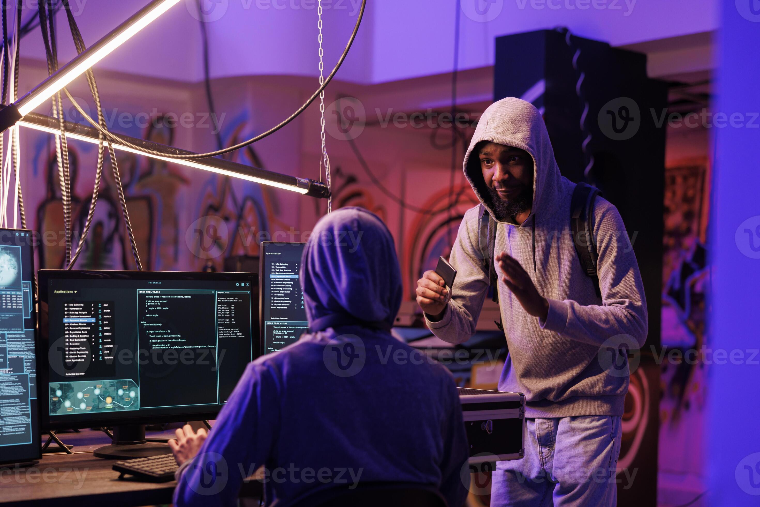 African american hacker holding ssd with illegal malware for password cracking. Criminal in hood ...