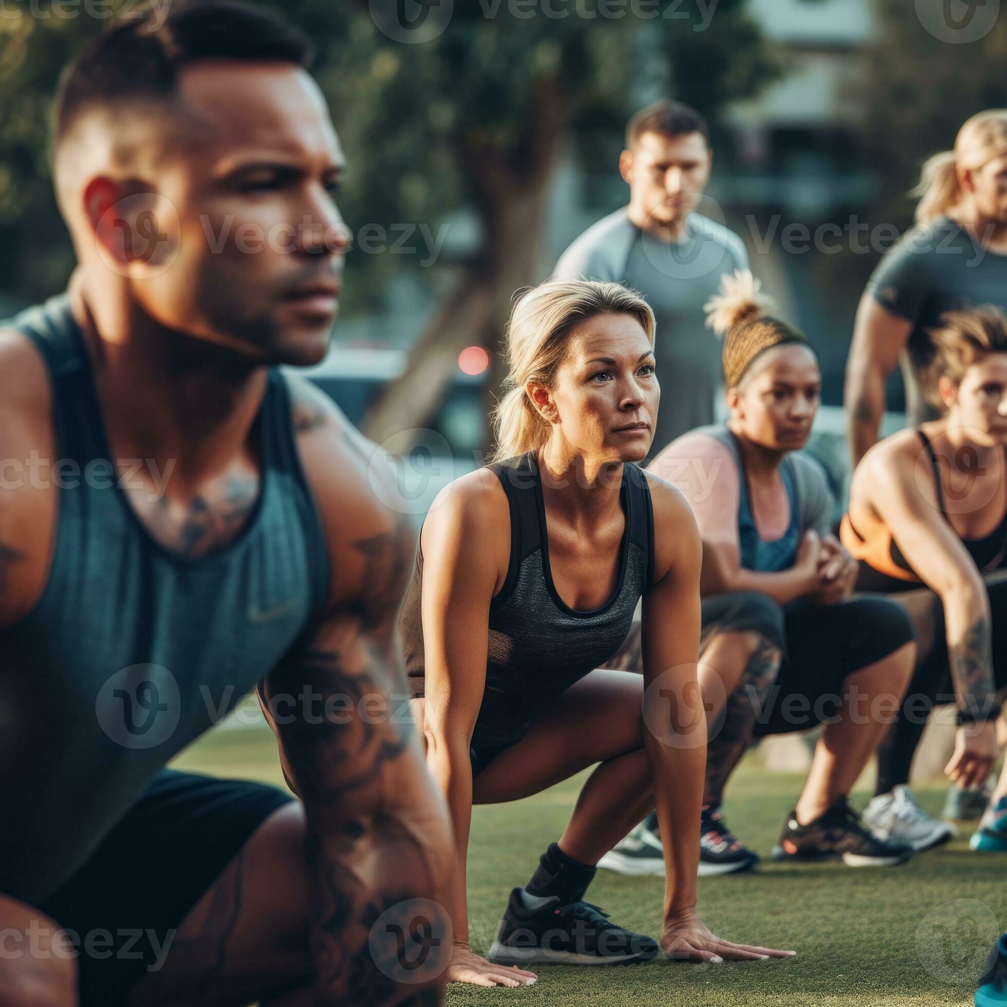 A group of fitness enthusiasts participating in a high-intensity exercise class in outdoor ...