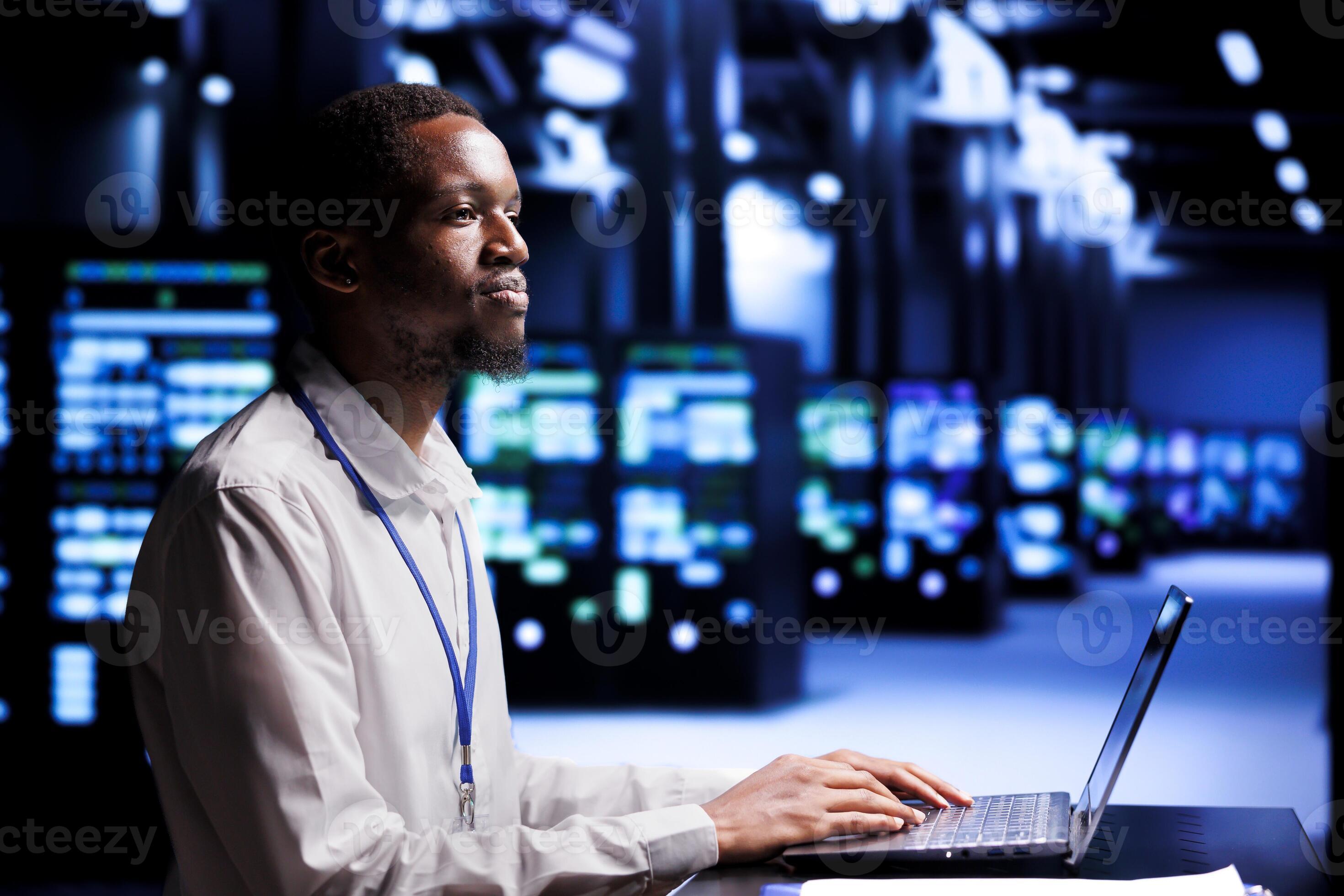 African american IT programmer in high tech facility using laptop to ...