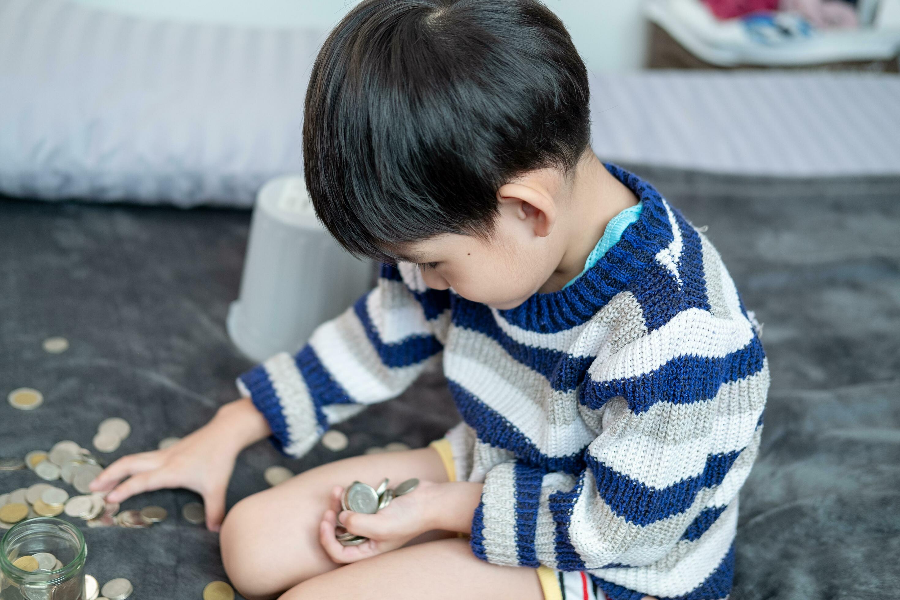 Asian boy happily counting coins to save money 32484529 Stock Photo at Vecteezy