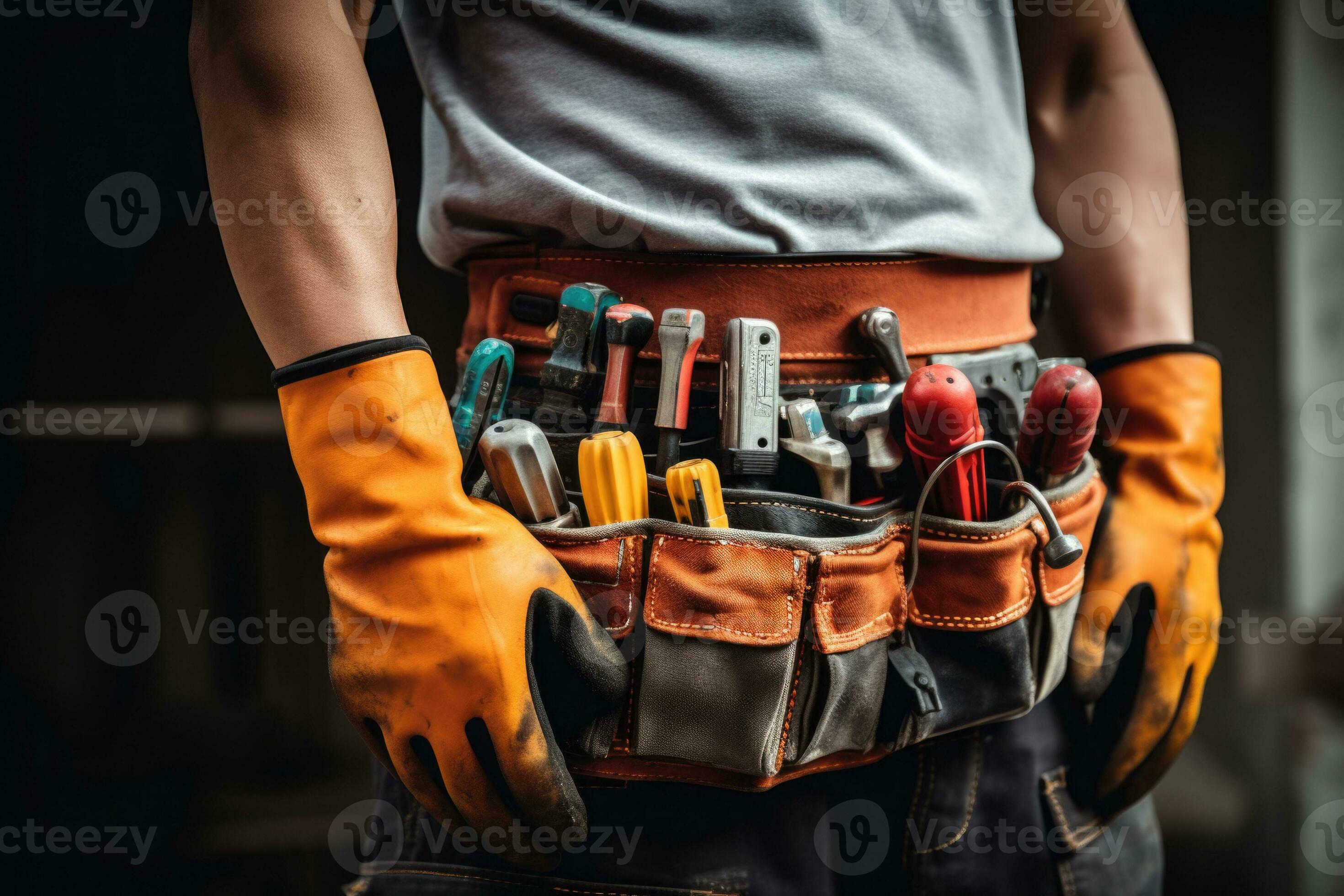 Handyman with tools belt. Detail of man hands holding work gloves and wearing tool kit on waist ...