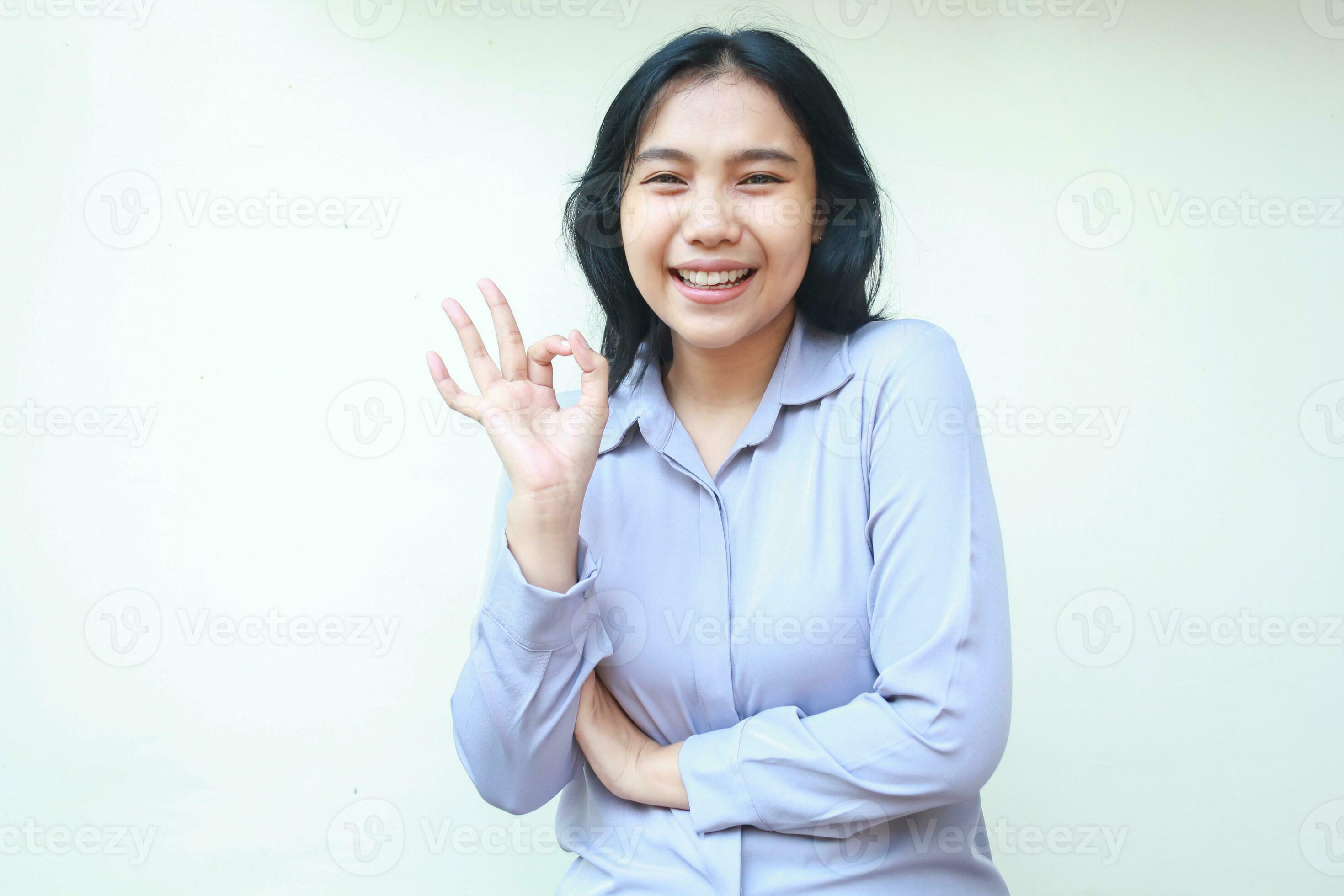 beautiful asian young business woman dressed in formal shirt posing ok sign with folded arm ...