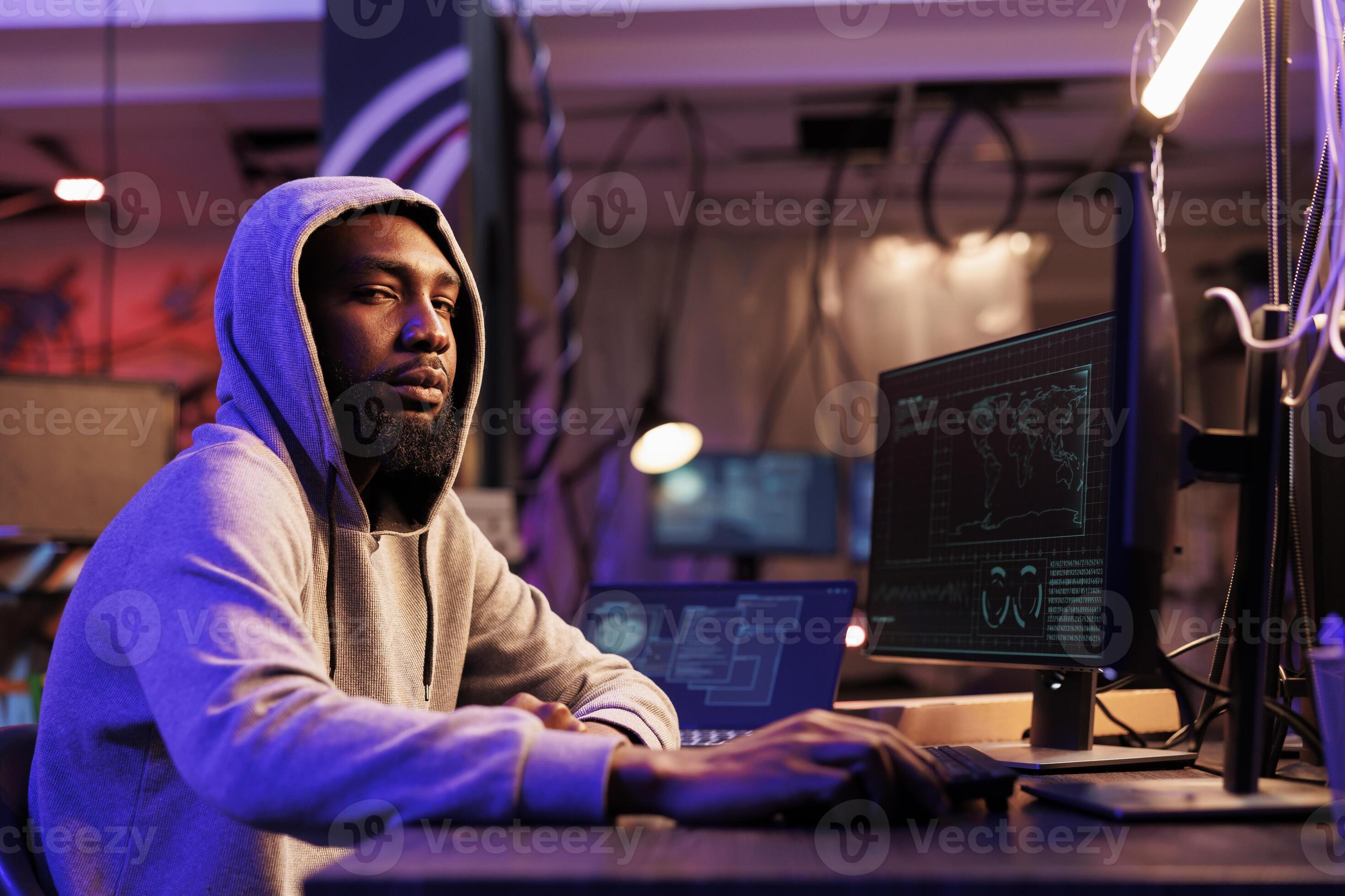 Hacker In Hood Hacking Computer System And Looking At Camera Young African American Man