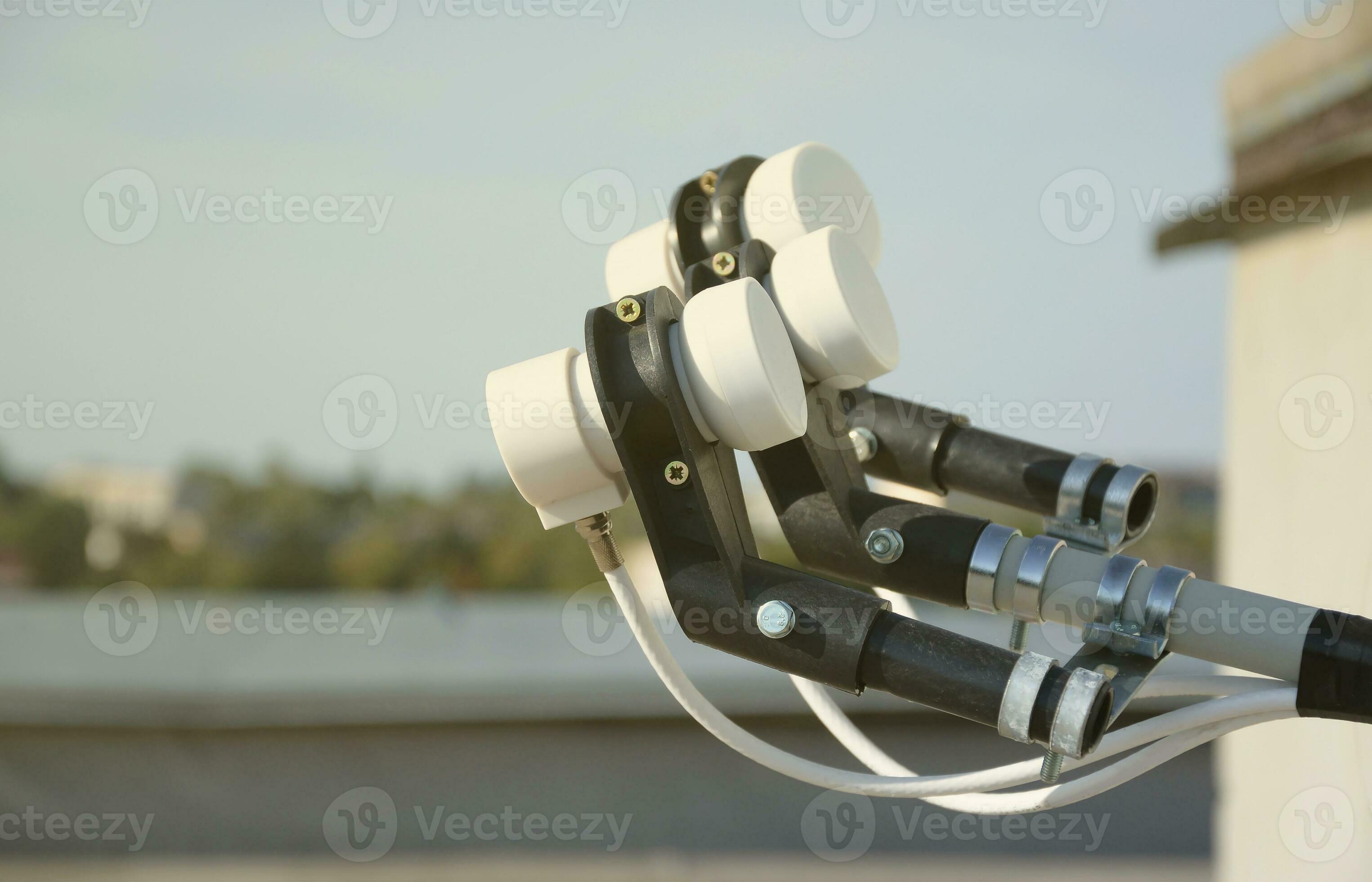 White satellite dish with three converters mounted on residental ...