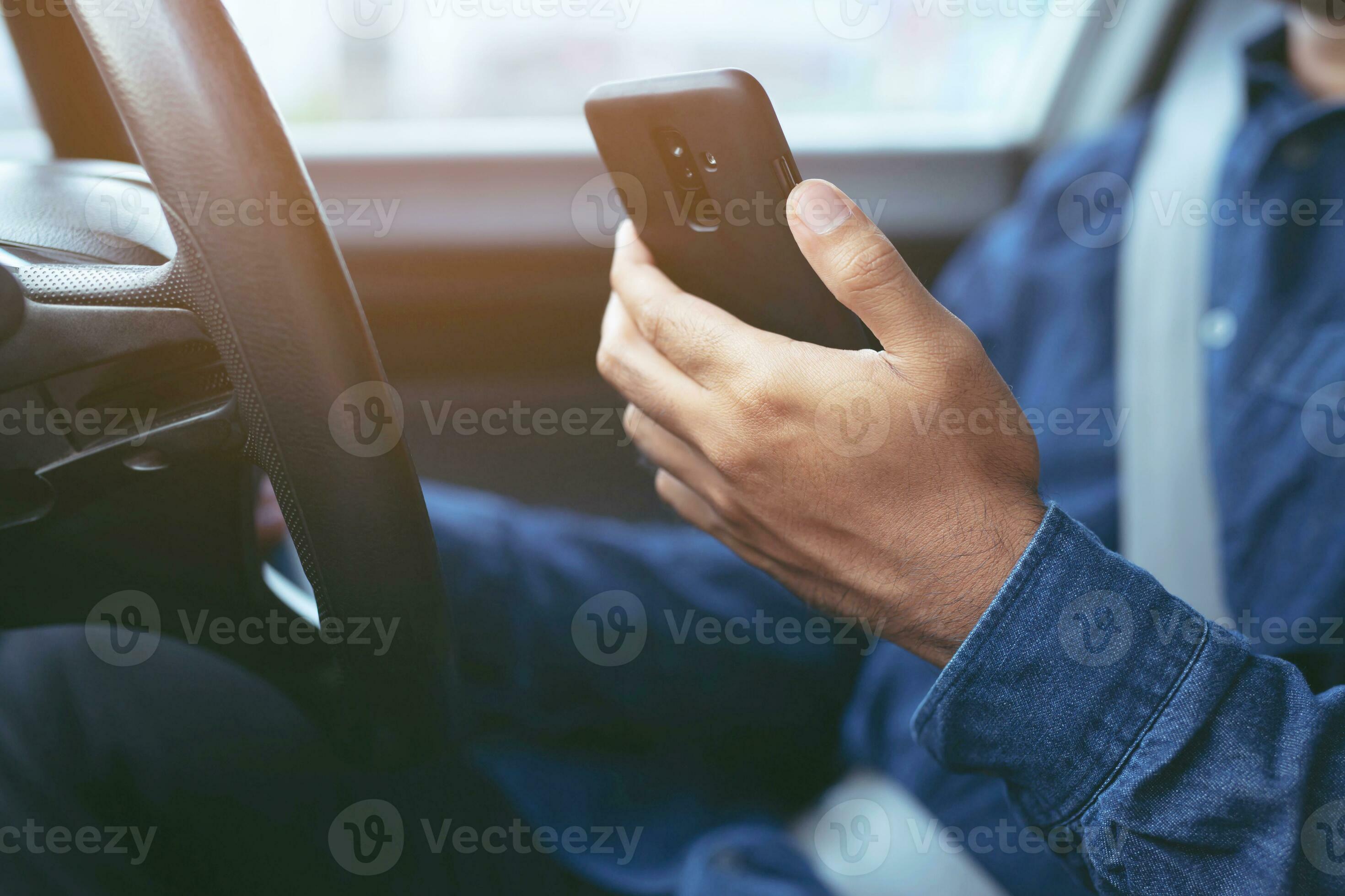 Young man driving using mobile smart phone while driving the car ...