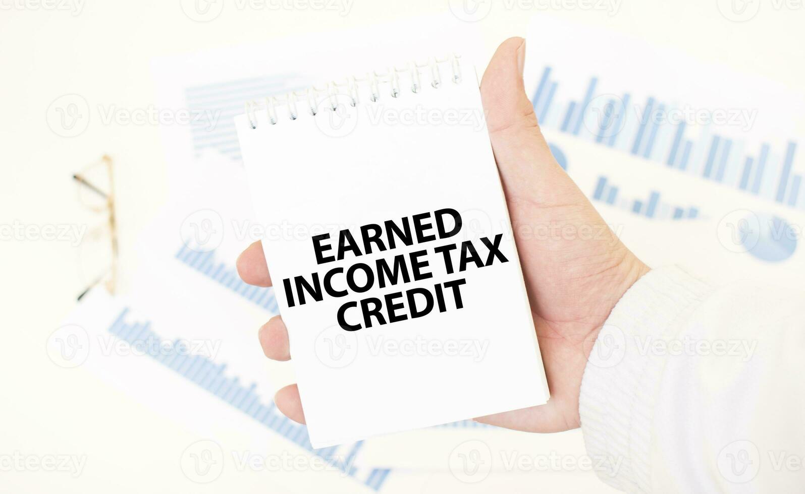 Businessman holding a white notepad with text EARNED INCOME TAX CREDIT, business concept ...