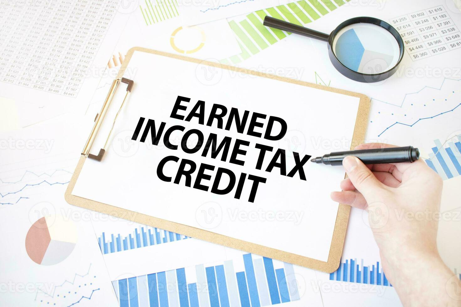 Text EARNED INCOME TAX CREDIT on white paper sheet and marker on businessman hand on the diagram ...