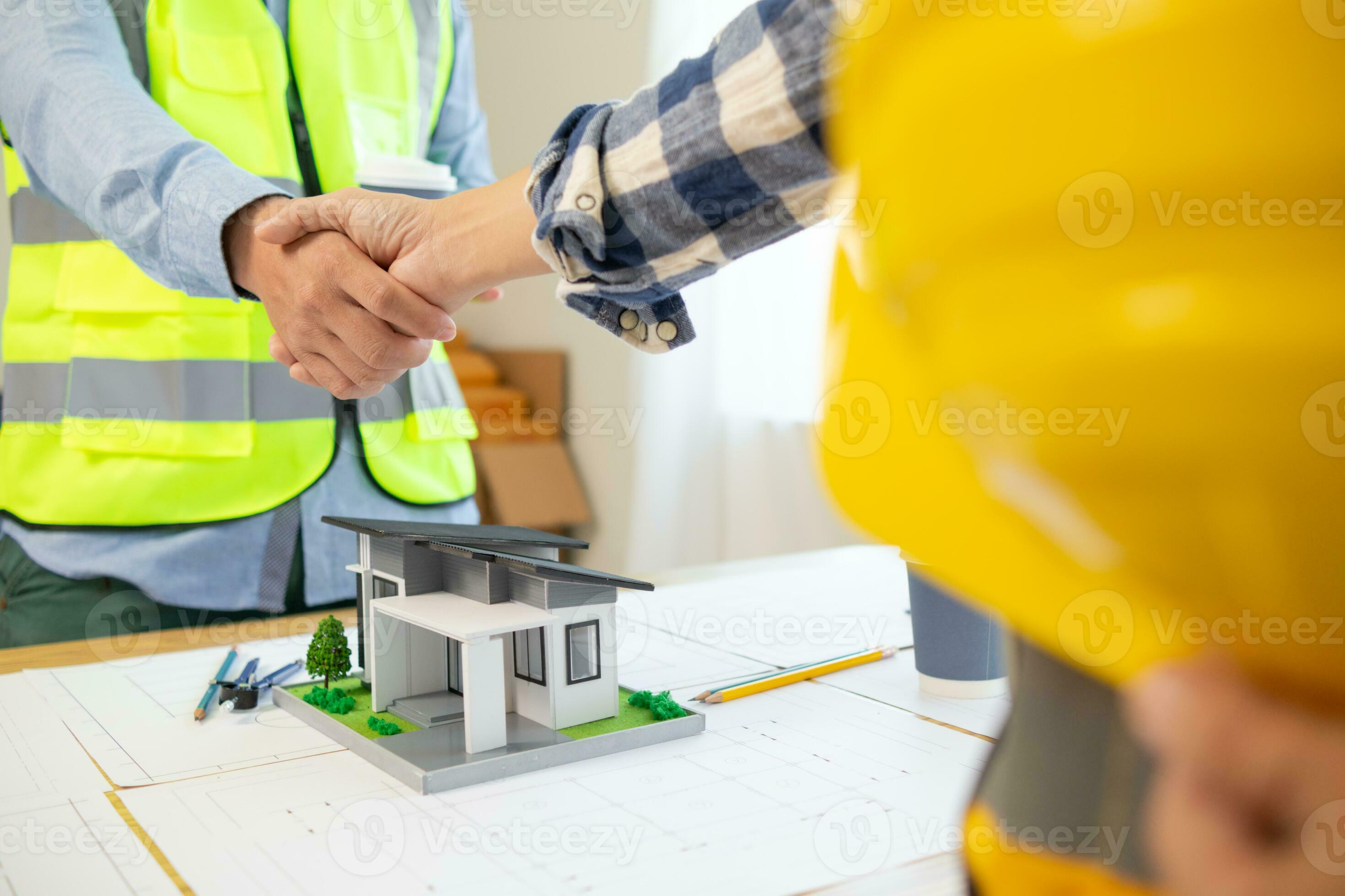 Architects and construction engineering handshake after meeting discuss structural blueprints ...