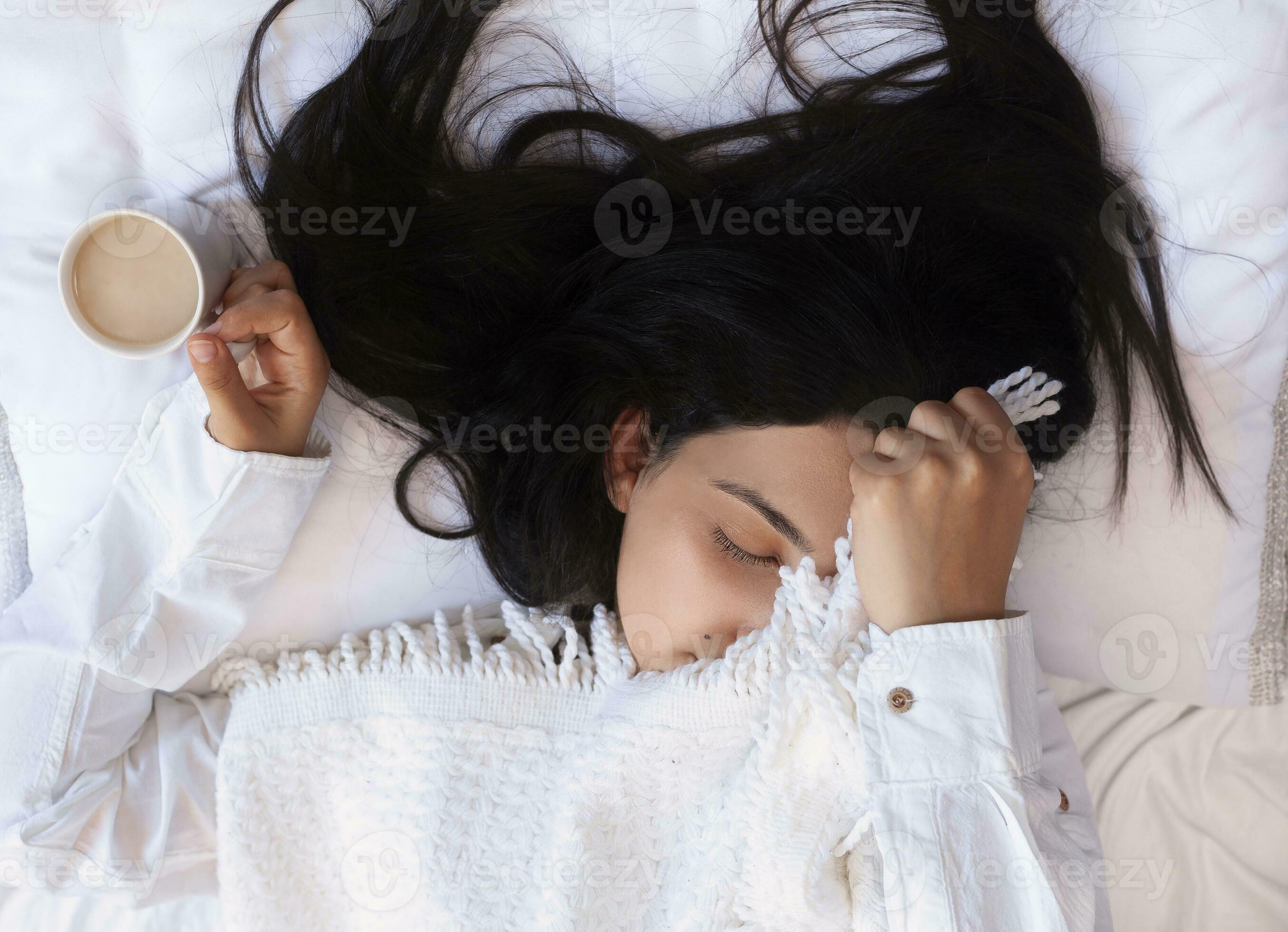 Beauty woman waking up in morning and drinking coffee in bed. Young beautiful woman in bed ...