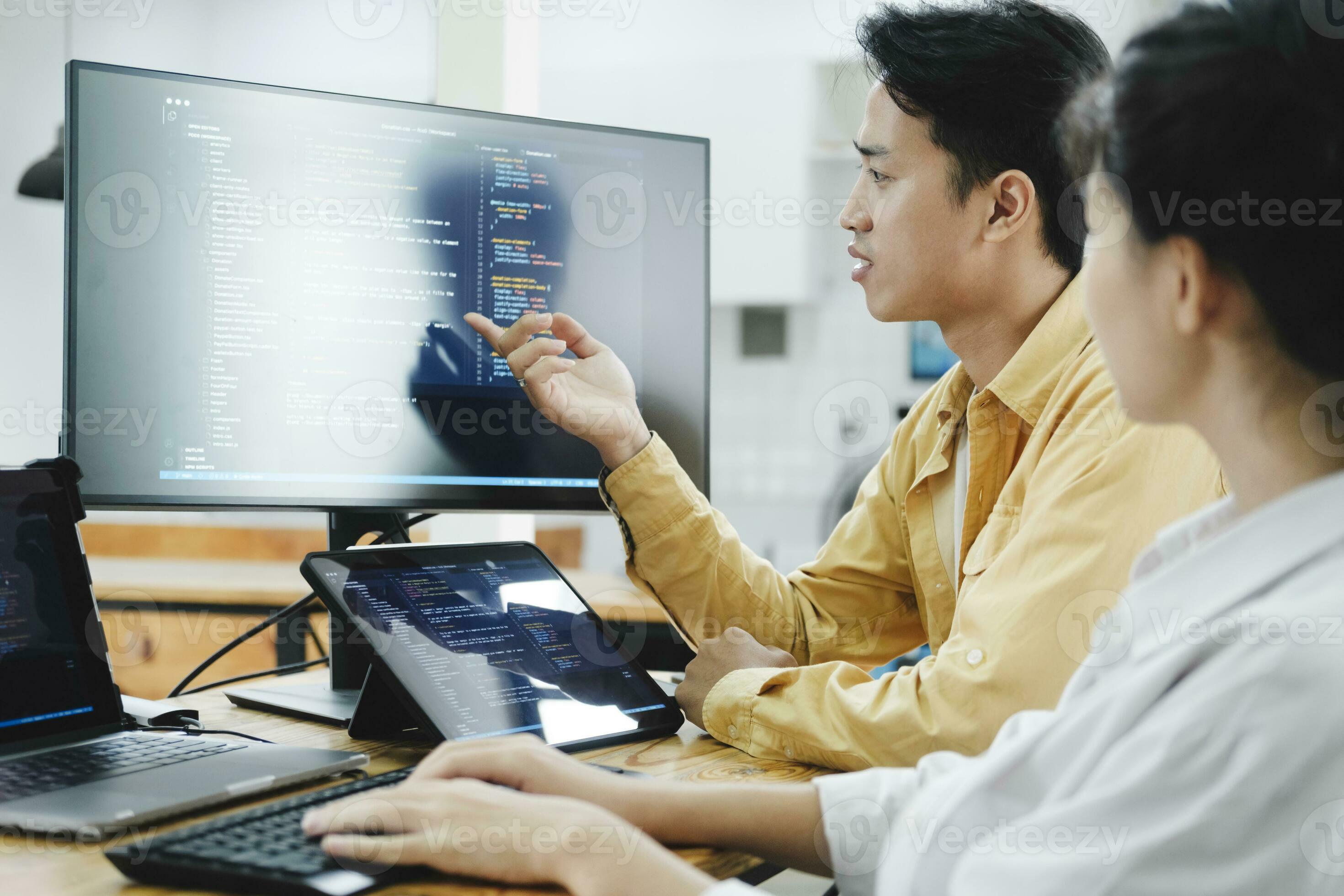 Team of young computer programmers cooperating while working on desktop ...