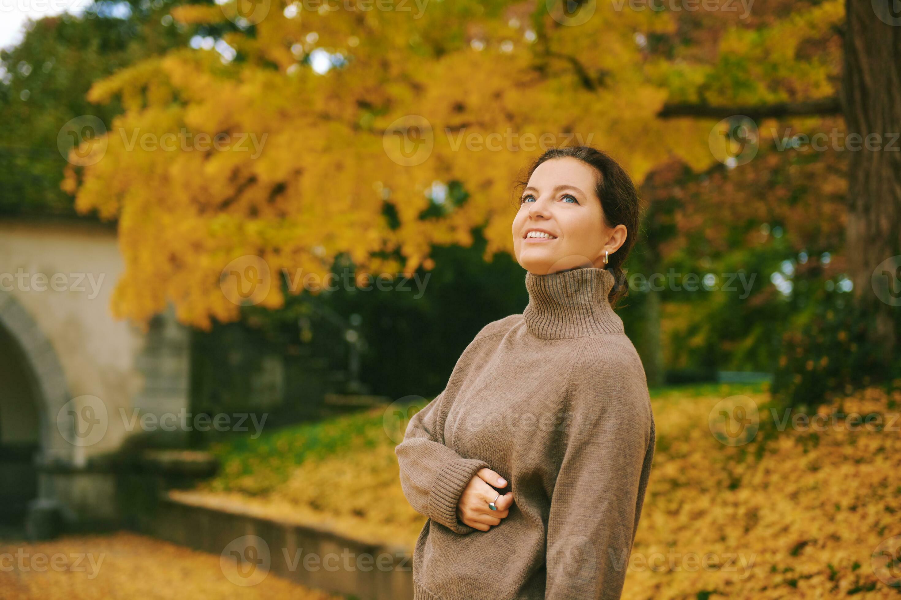 Autumn portrait of beautiful mature woman, relaxing in golden fall park ...