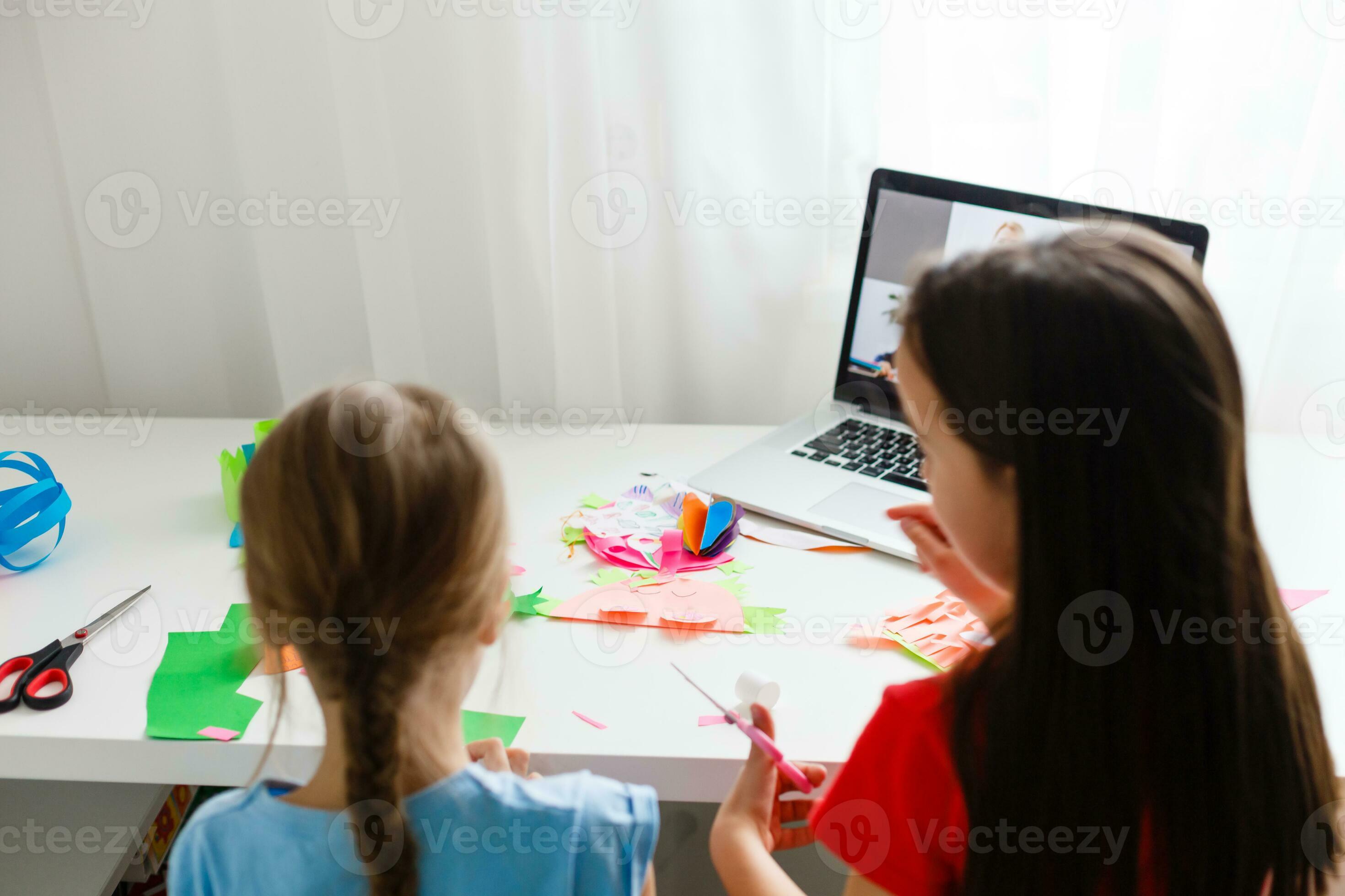 Cool online school. Kids studying online at home using a laptop. Cheerful young little girls ...