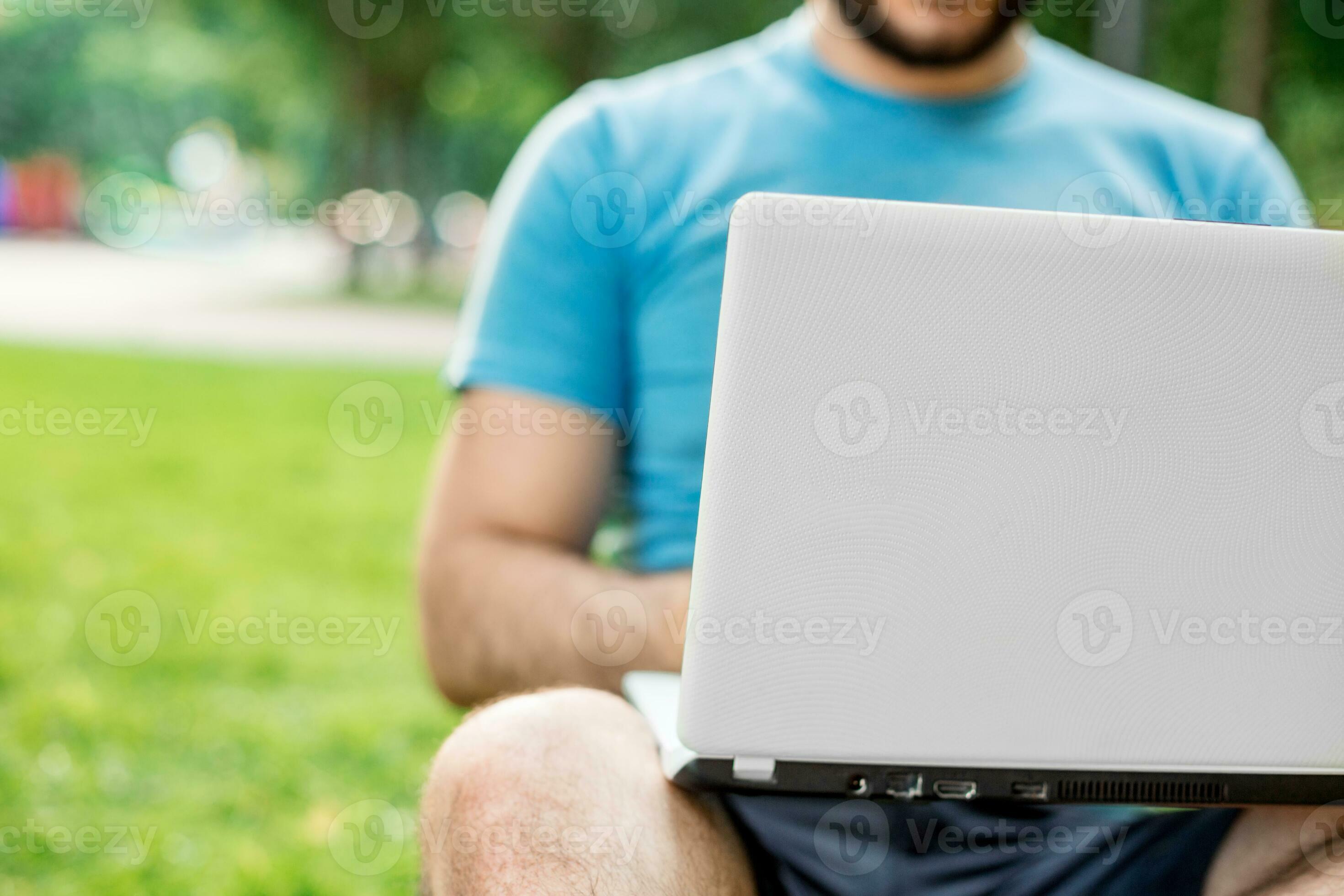 Young man using and typing laptop computer in summer grass. 35178501 Stock Photo at Vecteezy