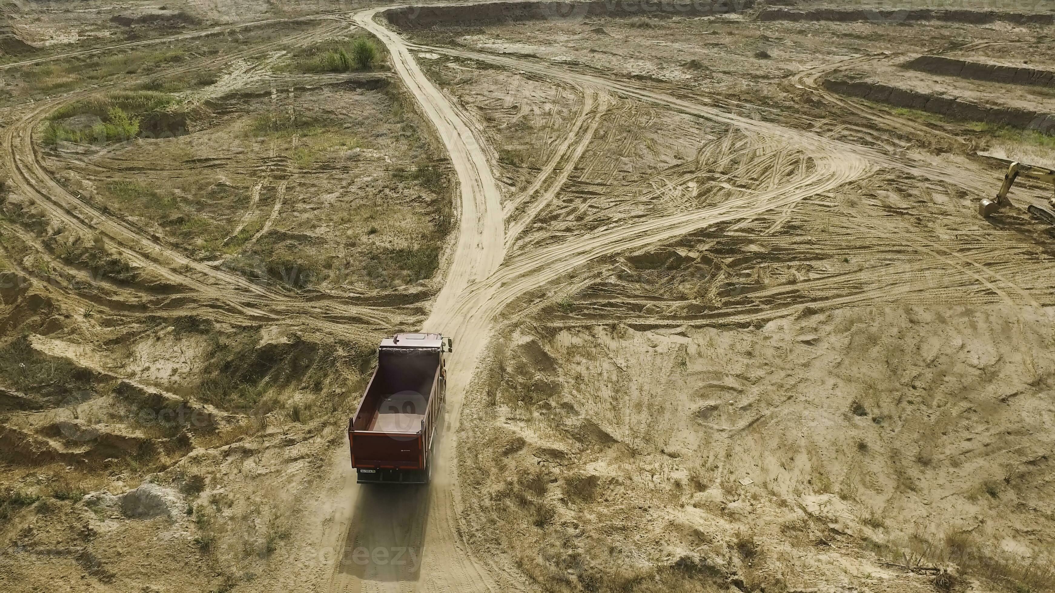 Dump truck driving on quarry area. Scene. Top view of dump truck driving through desert area ...
