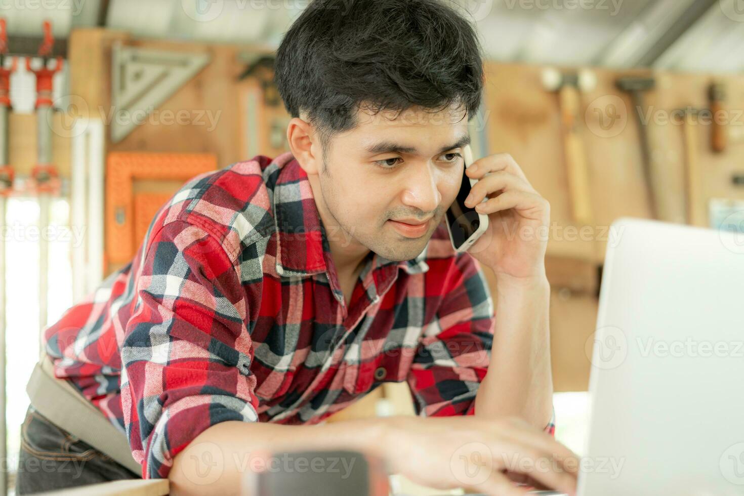 Asian man owner a small furniture business is recheck order online. carpenter male is adjust ...