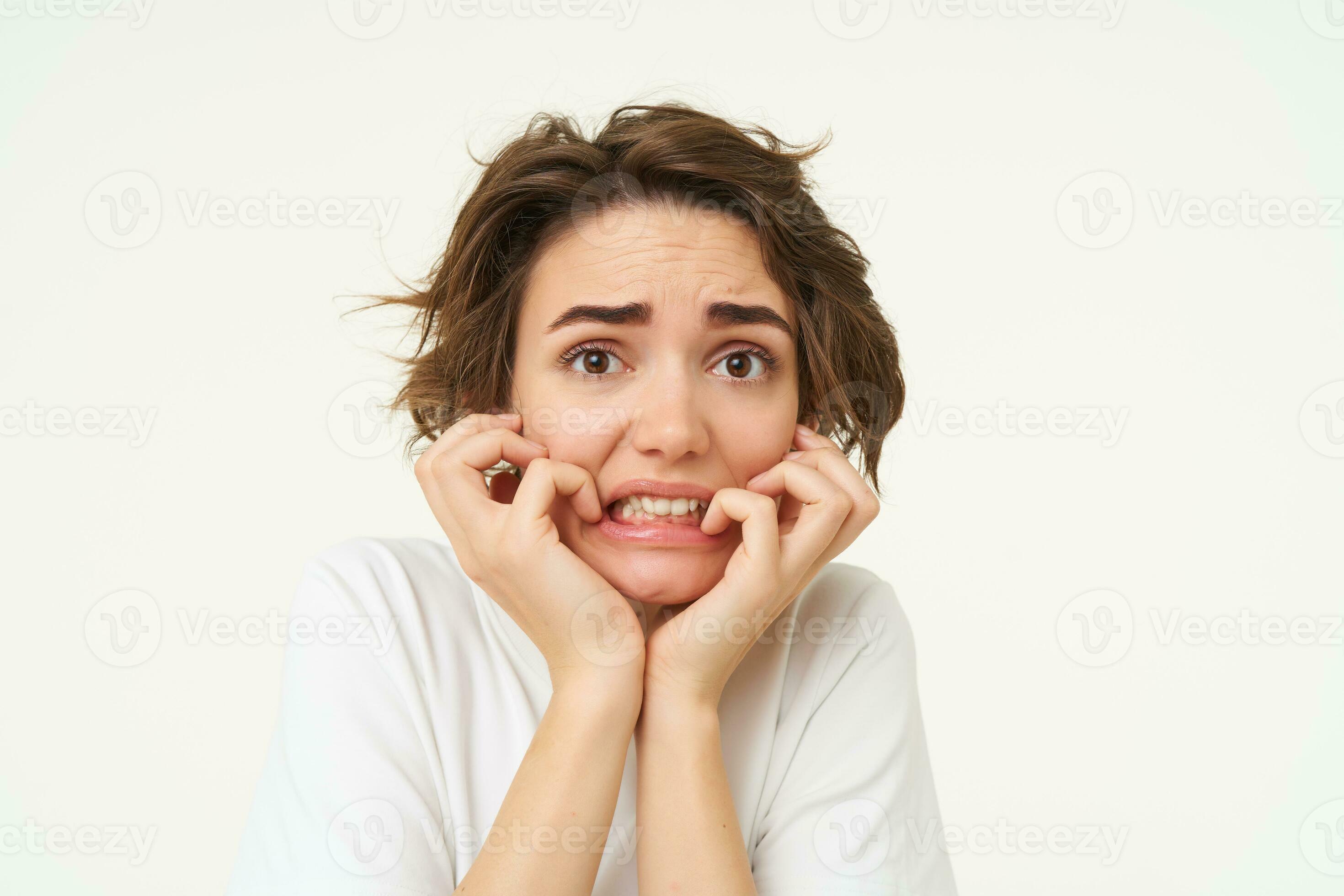 Close up of shocked, scared and worried young woman, trembling from fear, posing over white ...