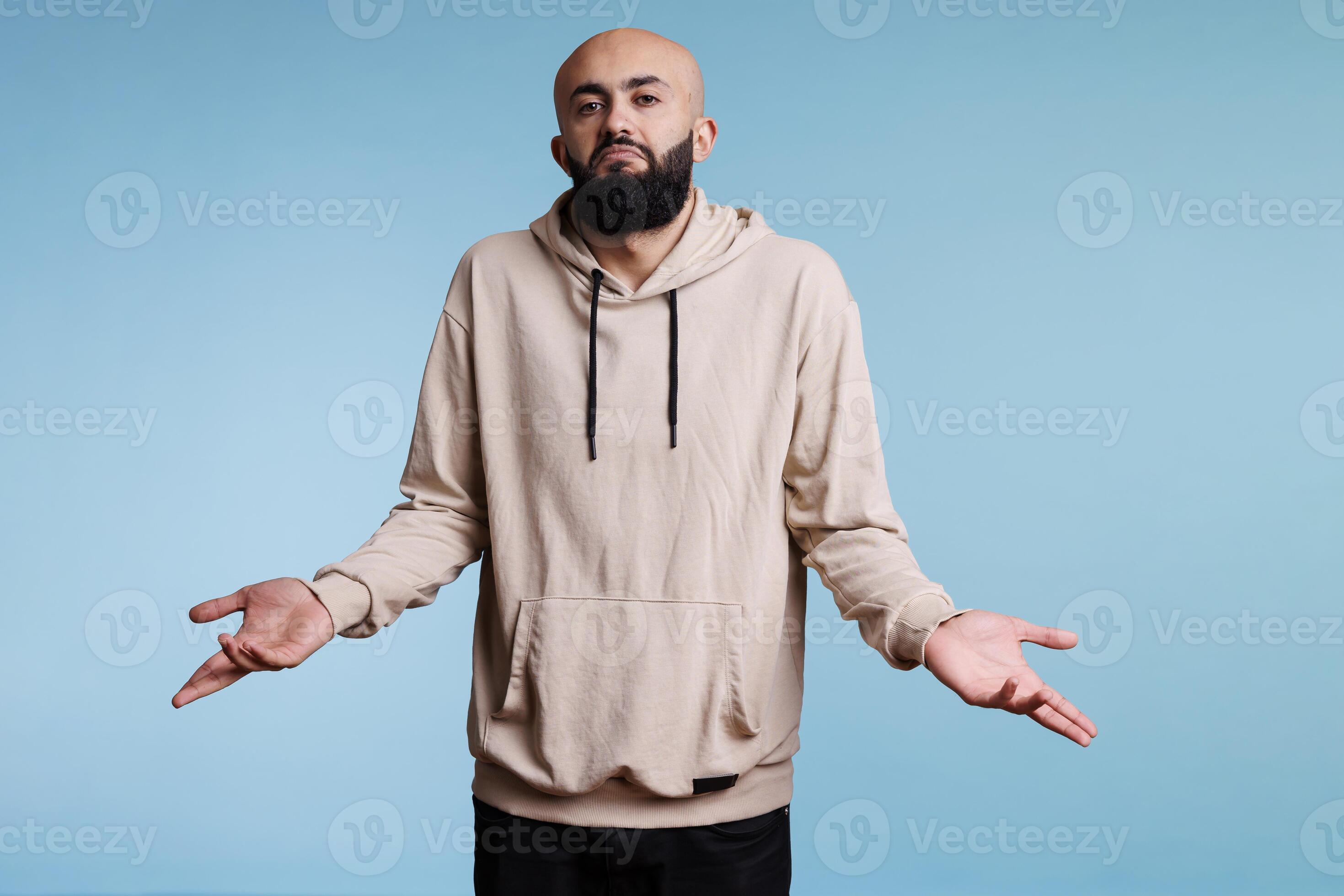Arab man shrugging shoulders in doubt and confusion while looking a ...
