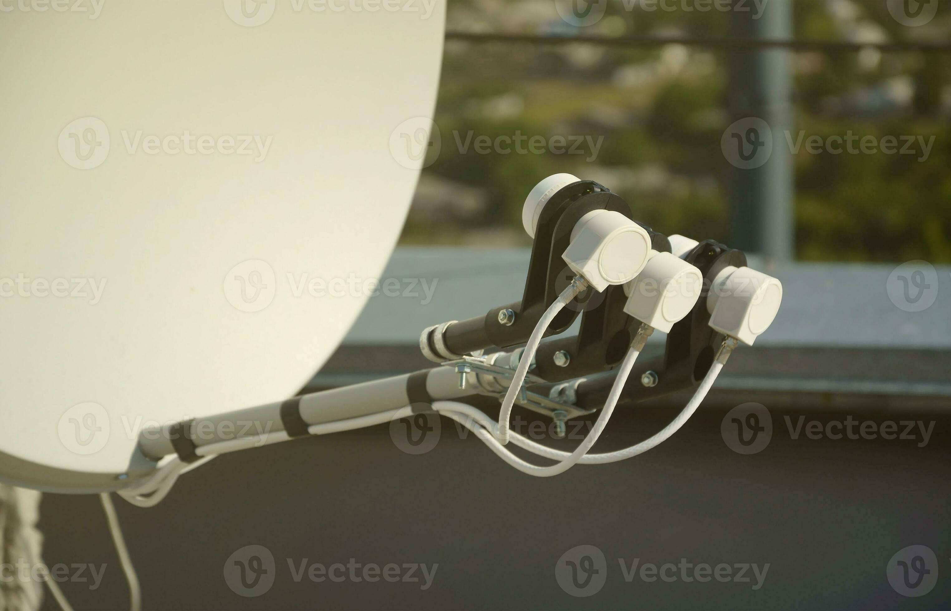 White satellite dish with three converters mounted on residental ...