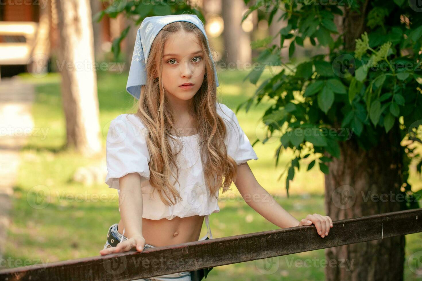 Pretty teenage girl posing near fencing in summer country estate ...