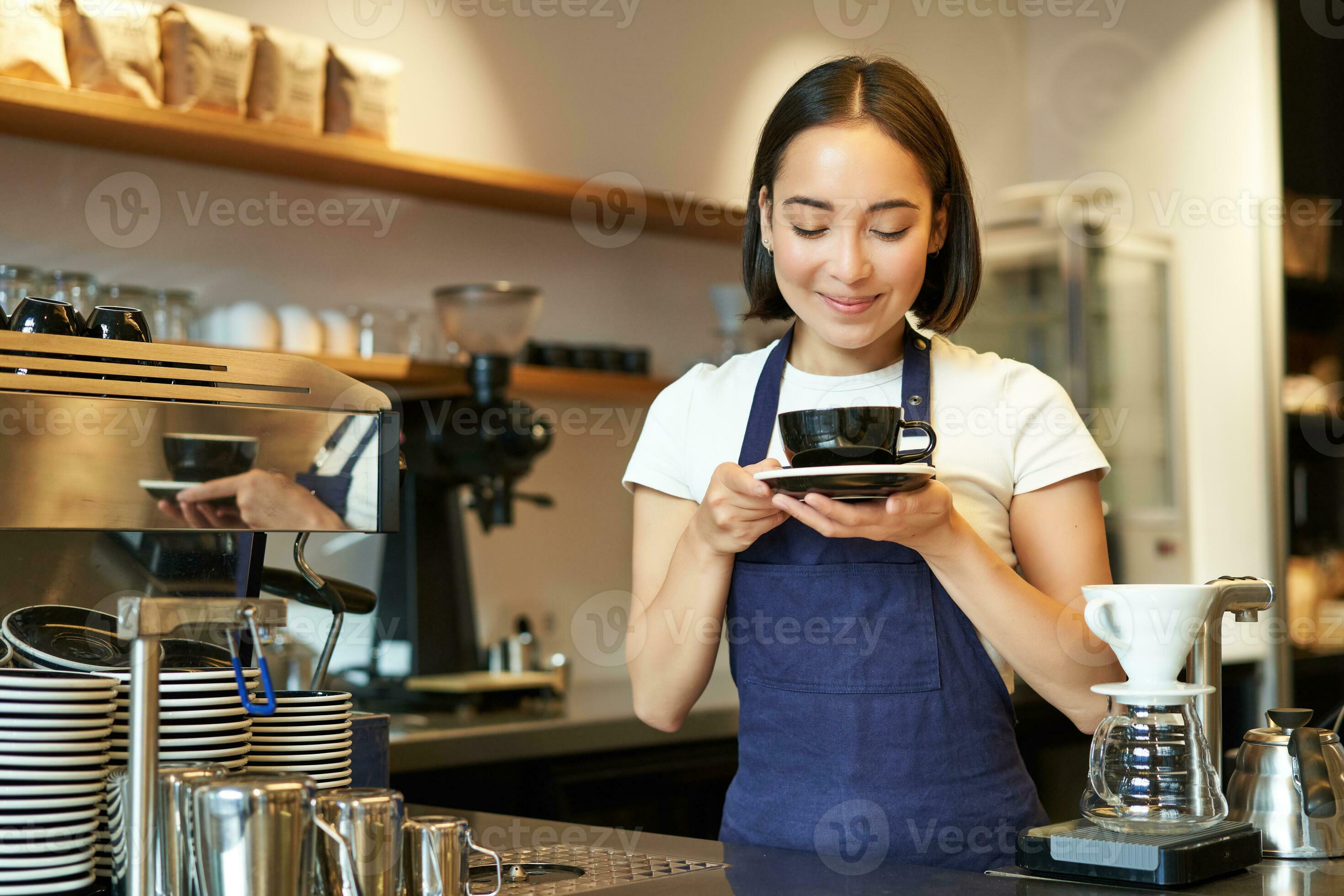 Smiling Asian Girl Barista Looking At Her Coffee Cup With Satisfaction Learning Latte Art