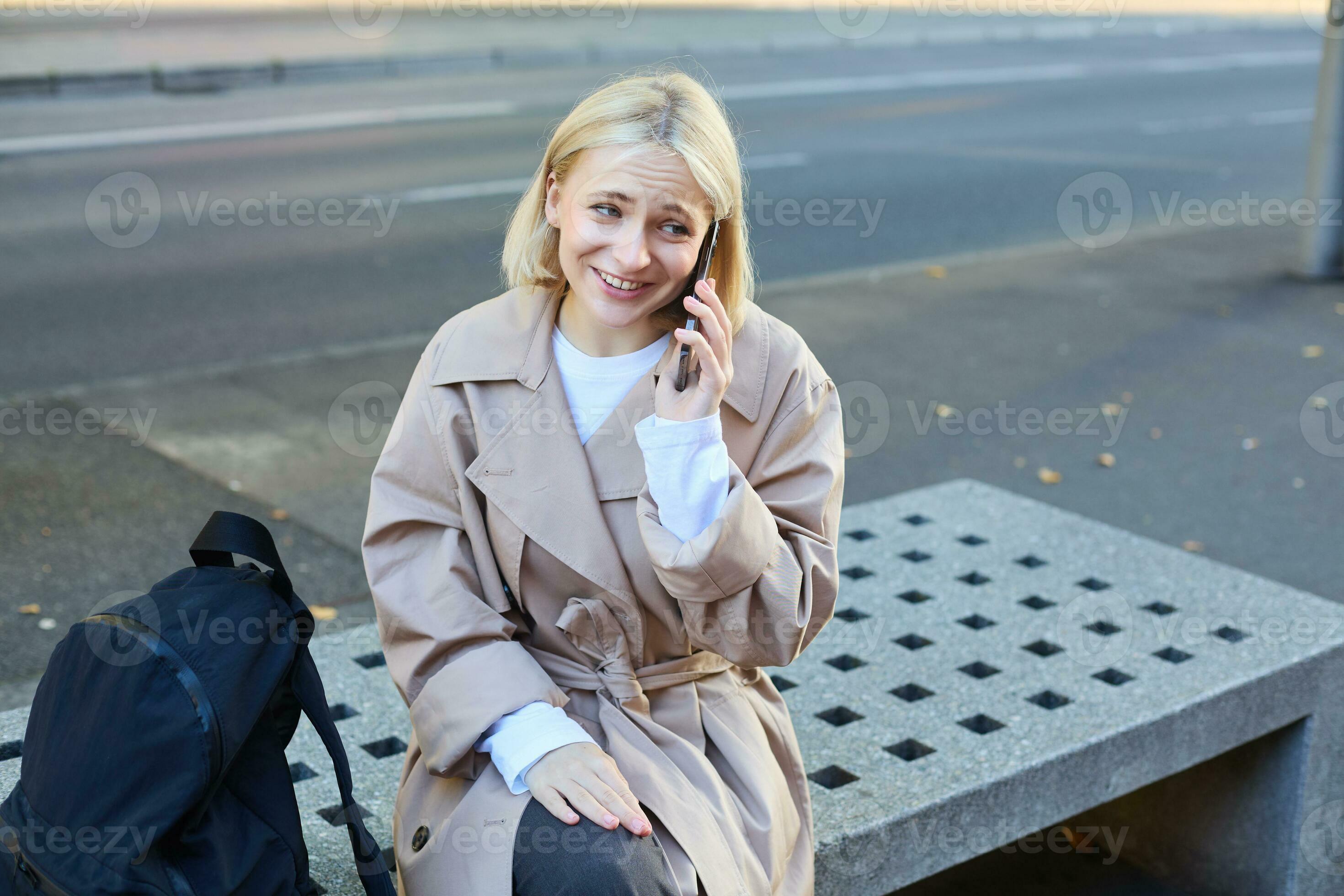 Image of carefree young candid woman, sitting on bench outside, talking ...
