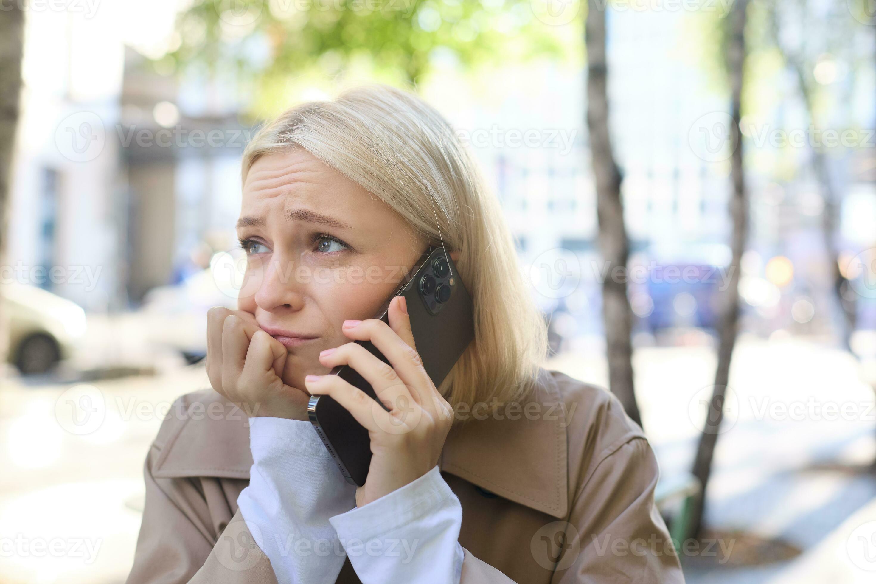 Image of young stressed, upset woman, talking on mobile phone with worried face expression, has ...