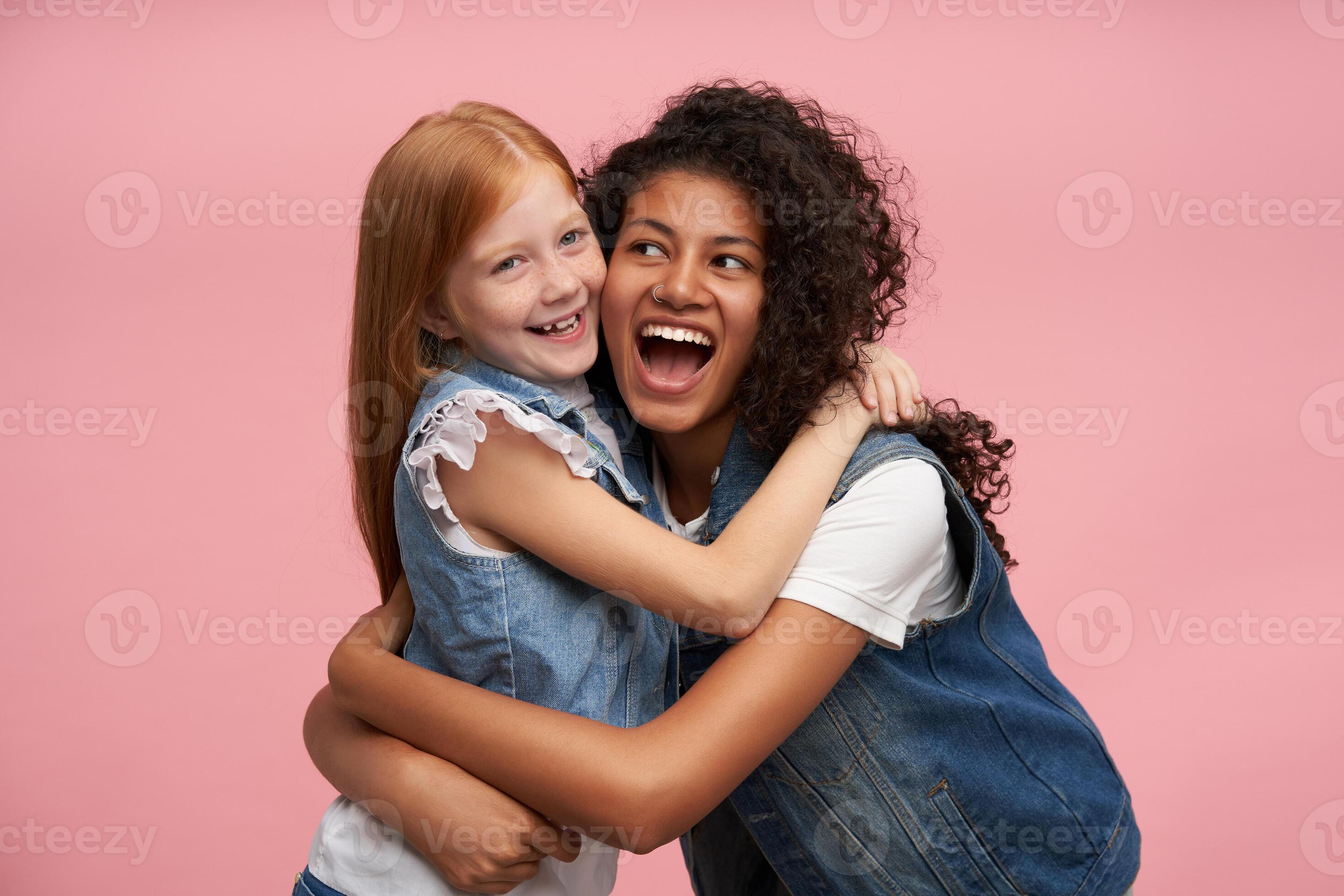 Two pretty young cheerful girls wearing family look while standing over ...