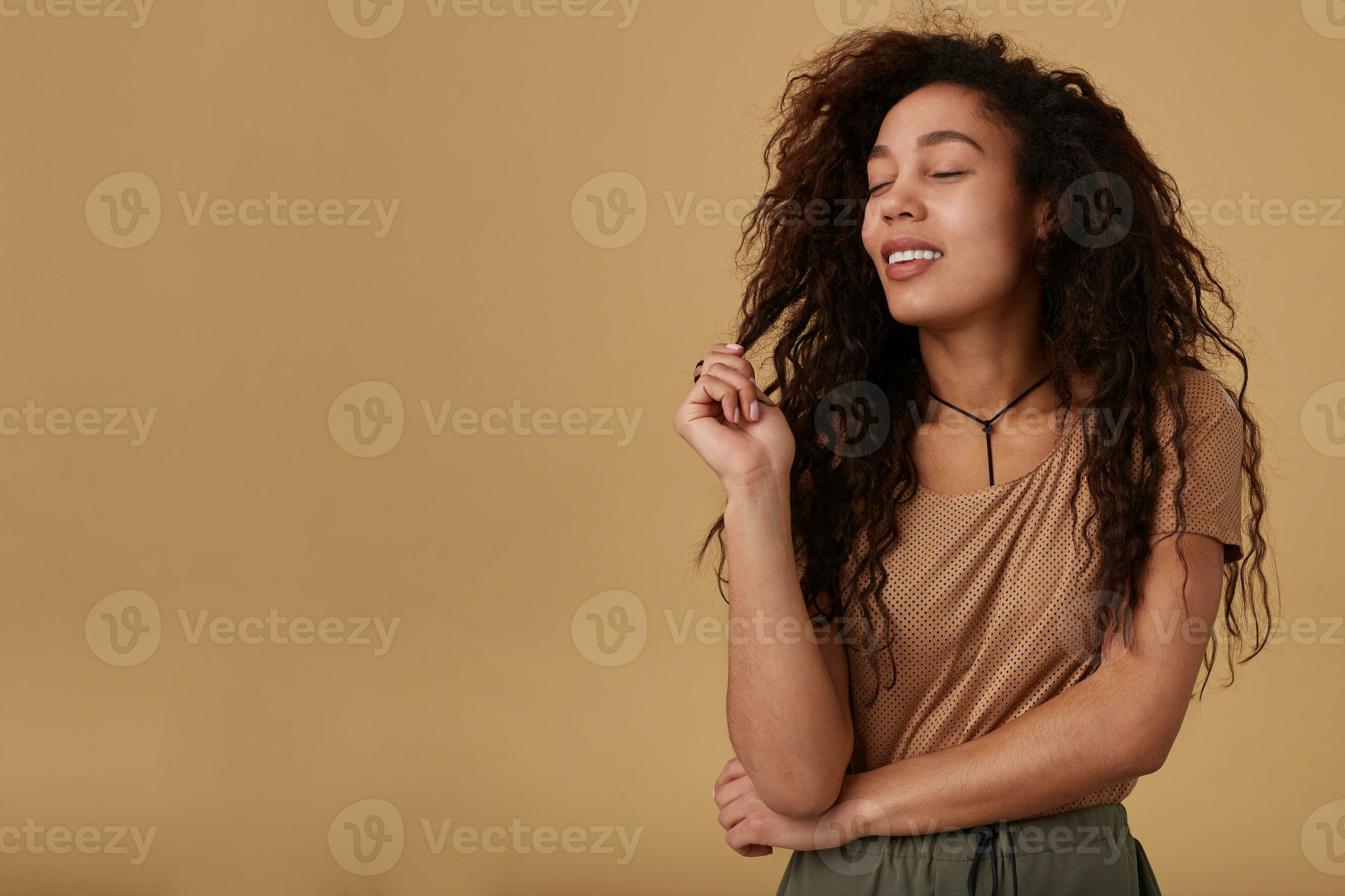 Pleased Young Long Haired Curly Dark Skinned Female With Casual
