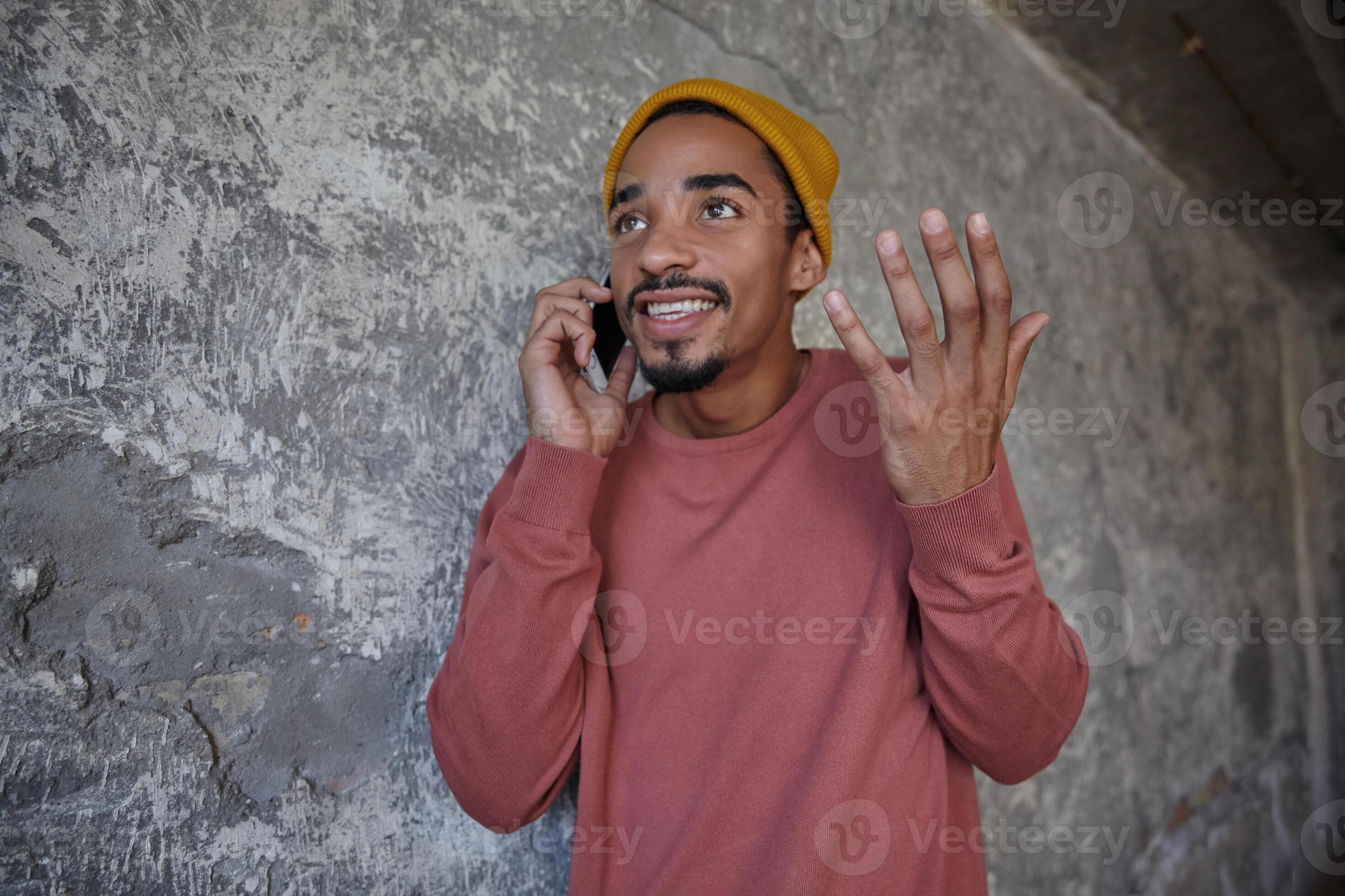 Portrait of excited lovely bearded dark skinned guy gesticulating while having conversation on ...