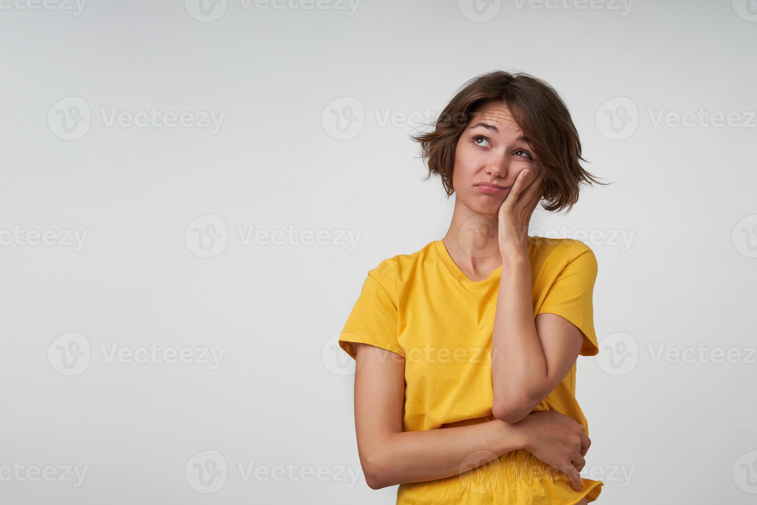 Studio shot of bored young brunette woman with short haircut looking ...