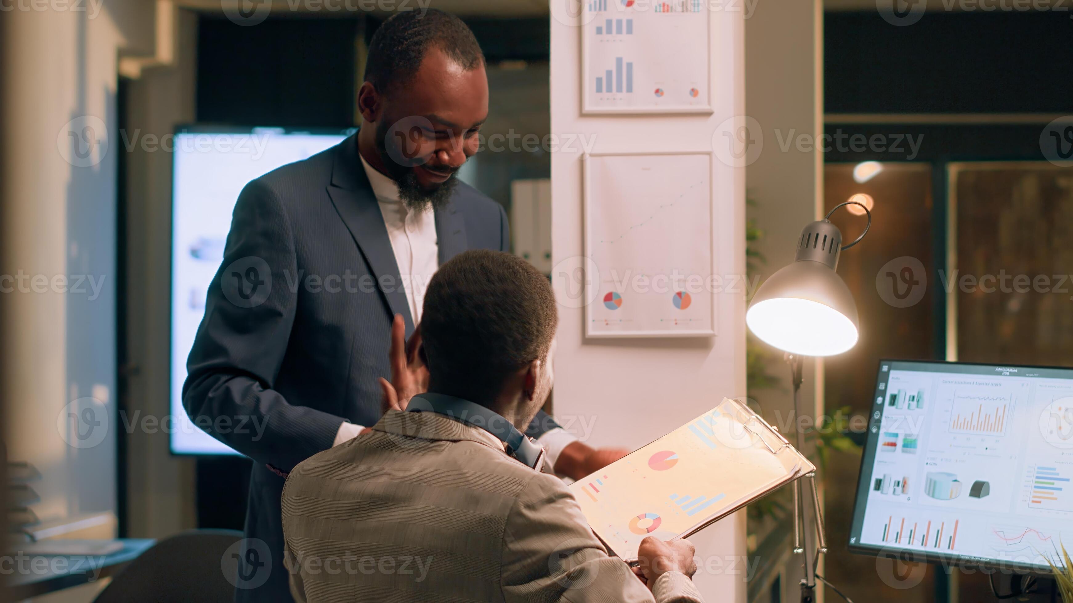 Friendly manager trying to make employee with headphones on pay attention at work in office ...