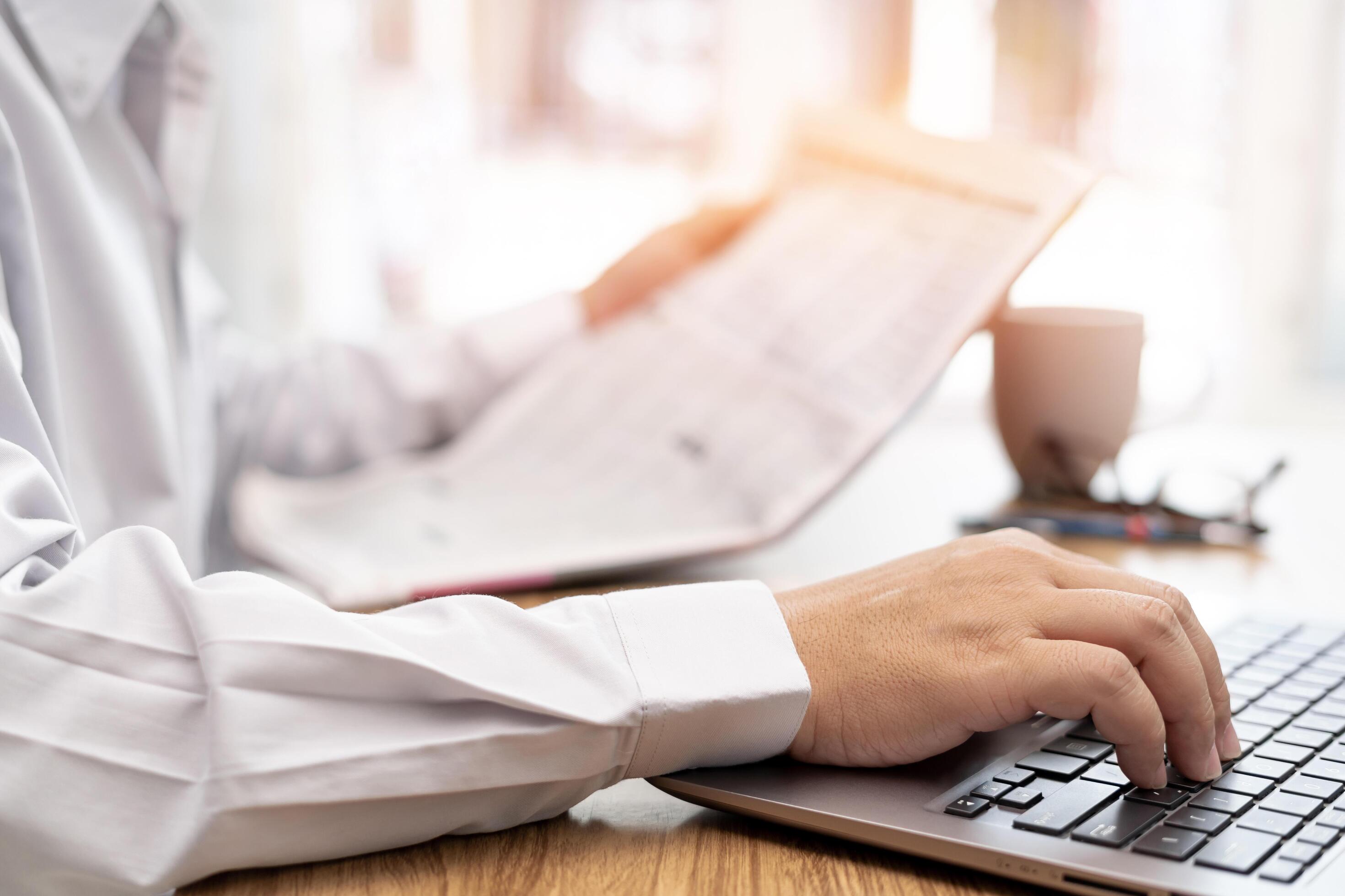 Business man use computer laptop and read newspaper with coffee cup on ...