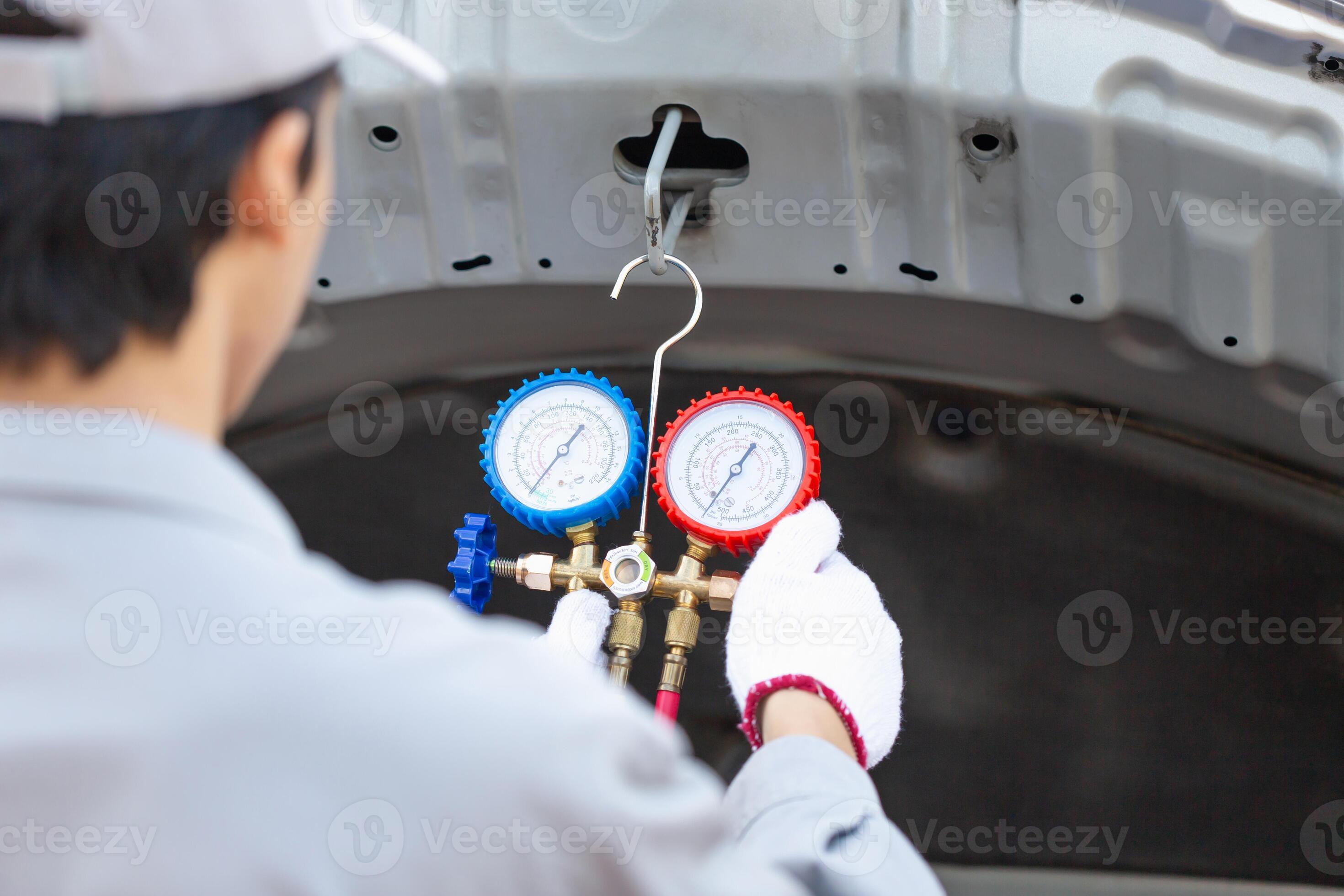 Technician check car air conditioning system refrigerant recharge, Repairman holding monitor ...