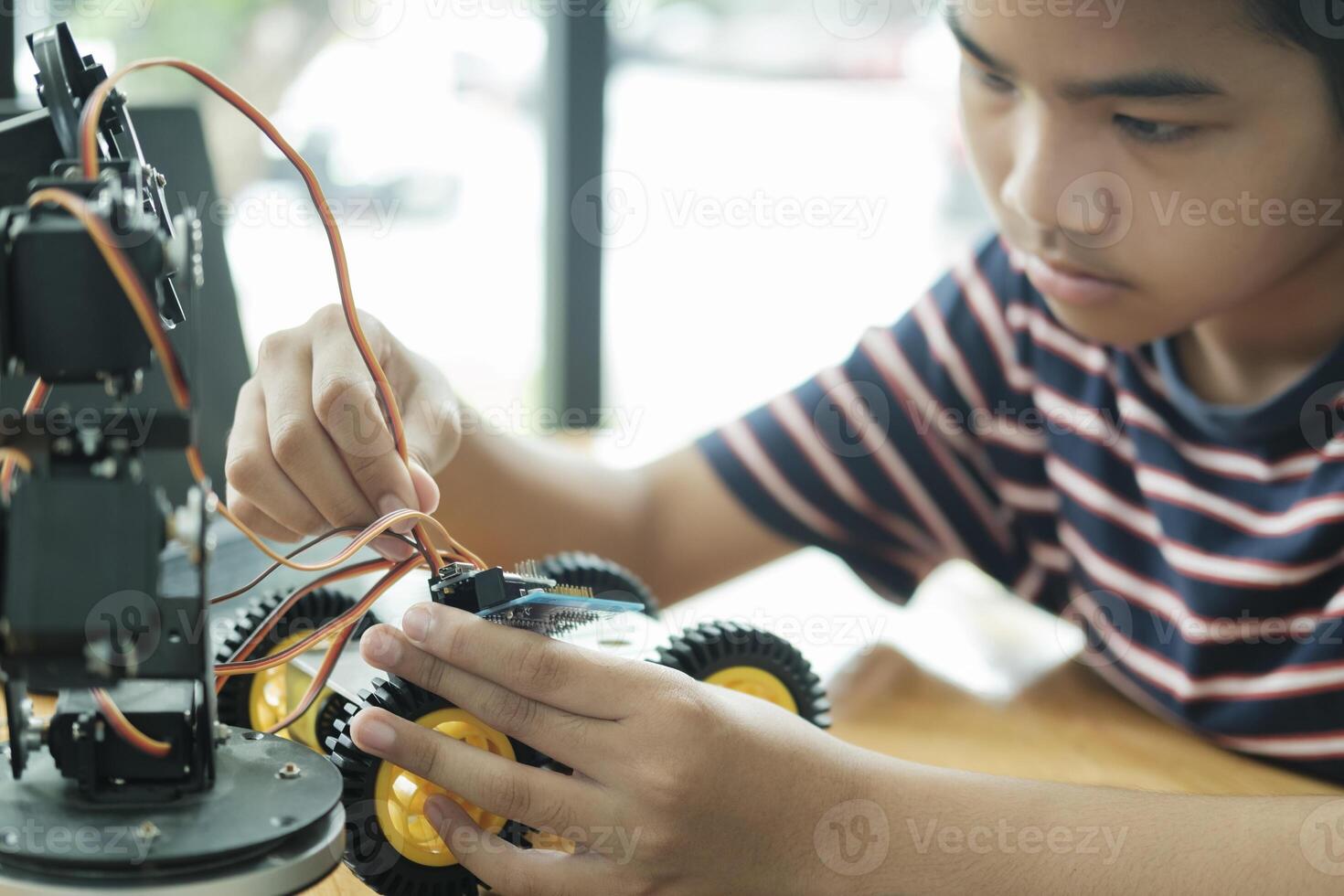 Asian teenager doing robot project in science classroom. technology of ...
