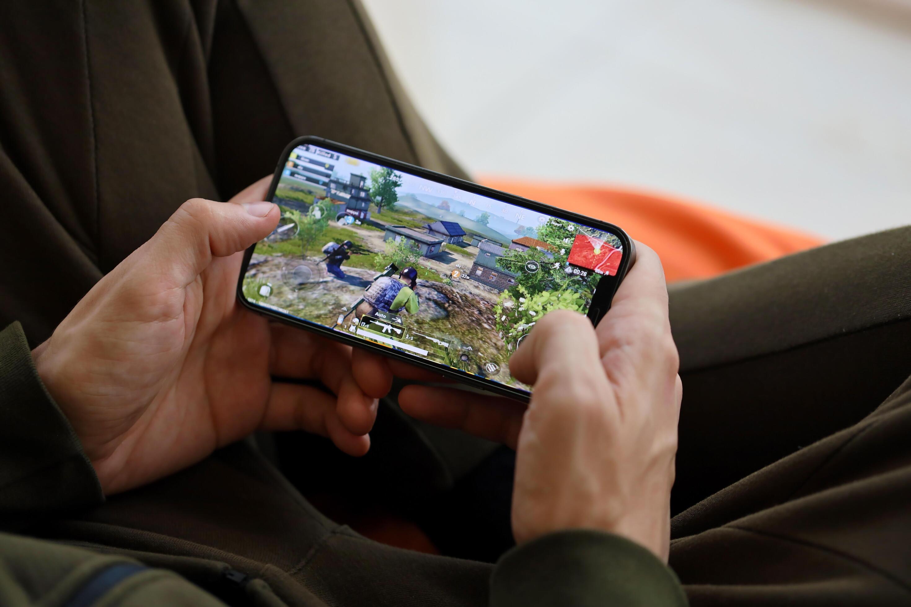 PUBG PlayerUnknowns Battlegrounds mobile iOS game on iPhone 15 smartphone screen in male hands ...