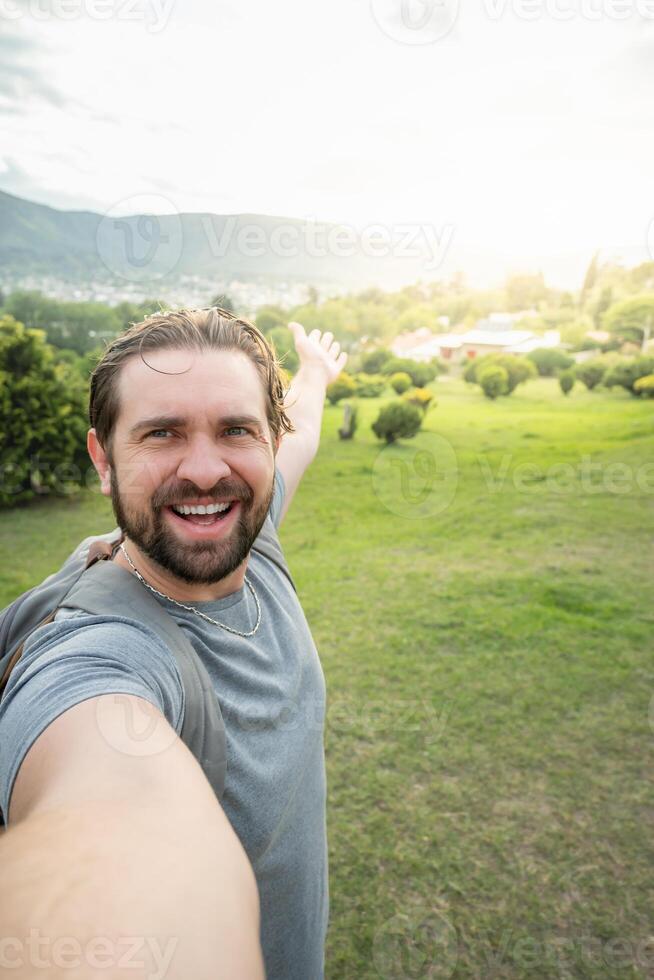 Young man with backpack taking selfie portrait on a mountain. Smiling ...