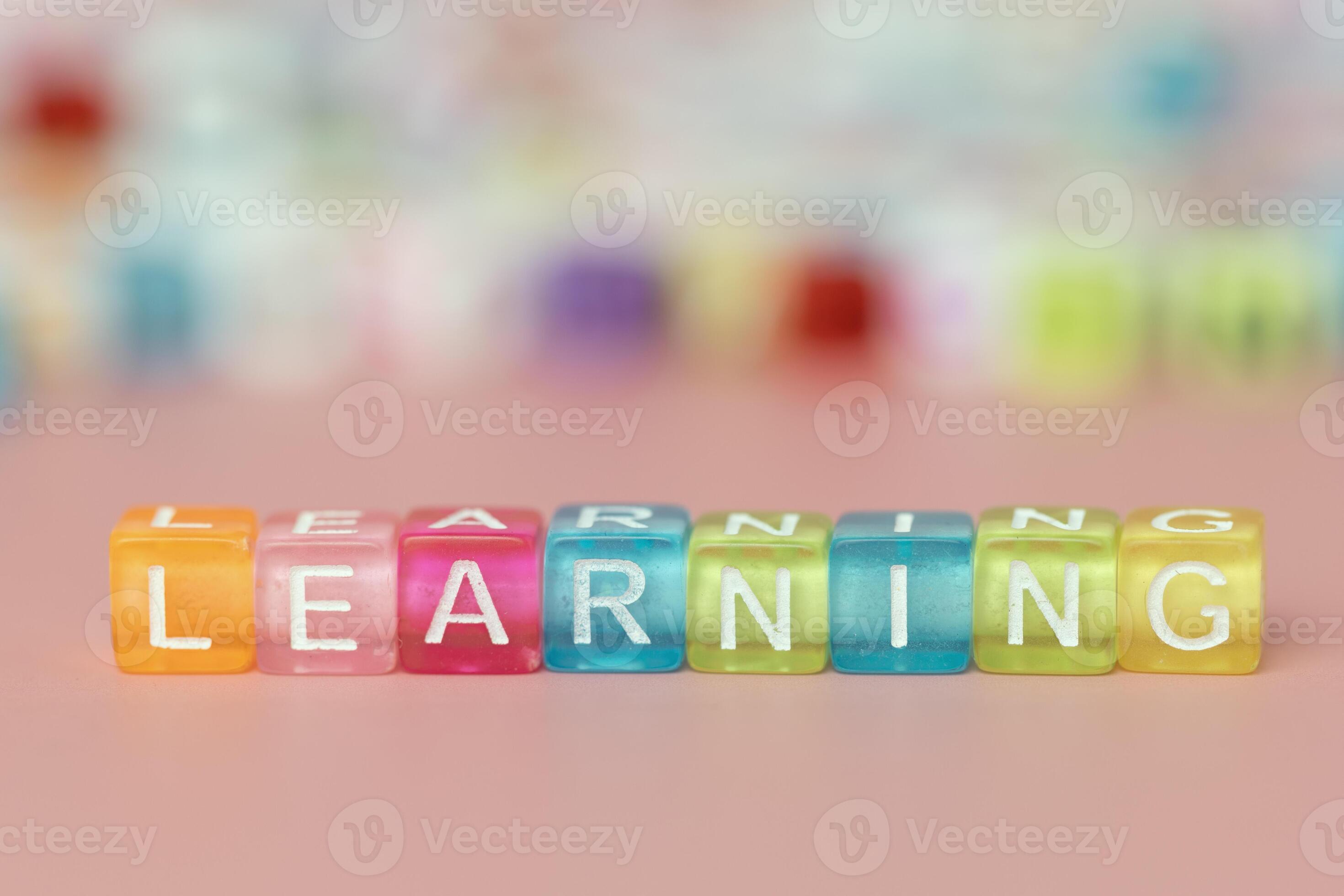 The word Learning formed with multicolored cubes on a pink background ...