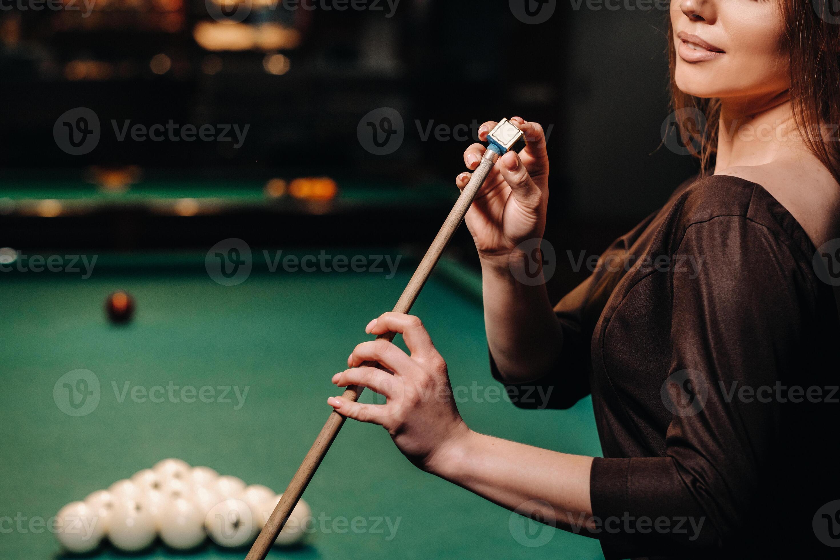 A Girl In A Dress Stands With A Cue In Her Hands And Cleans It With