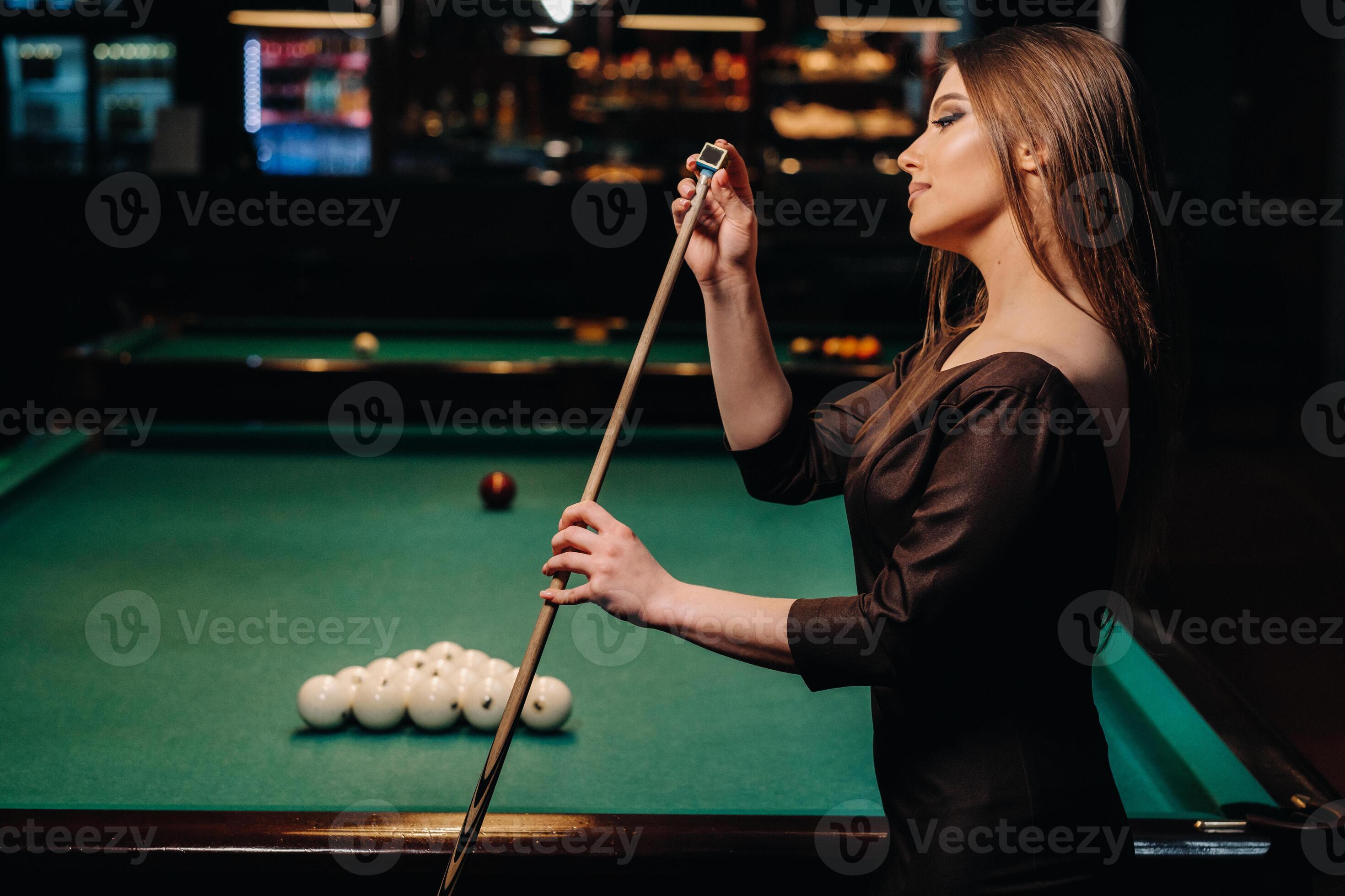 A Girl In A Dress Stands With A Cue In Her Hands And Cleans It With